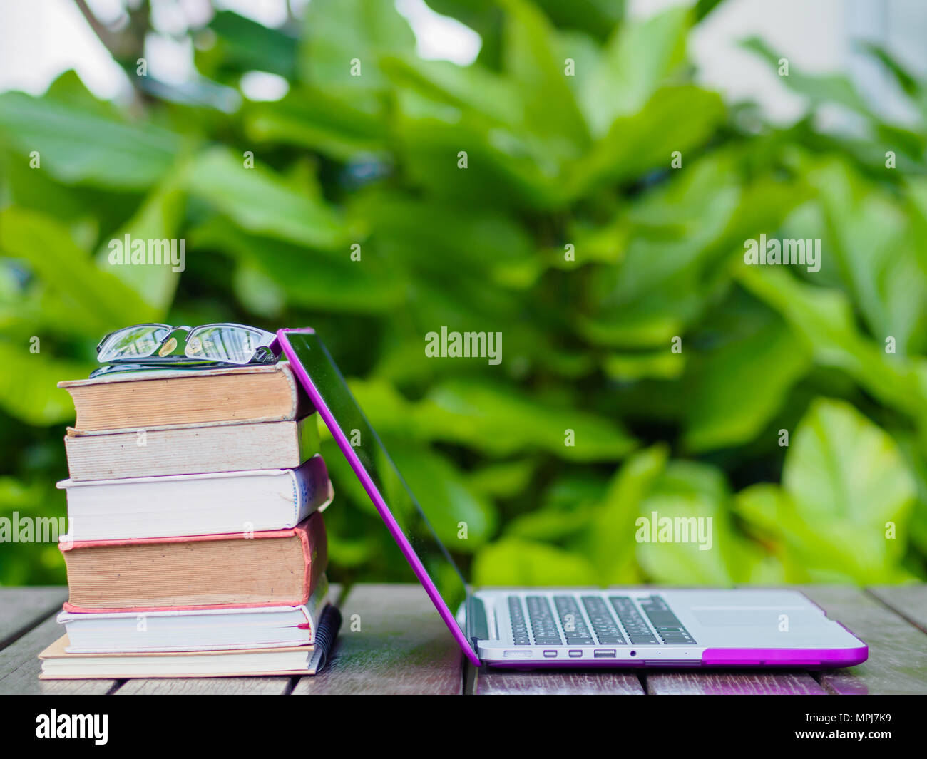 Stack of books with laptop on wood table outdoor Stock Photo - Alamy
