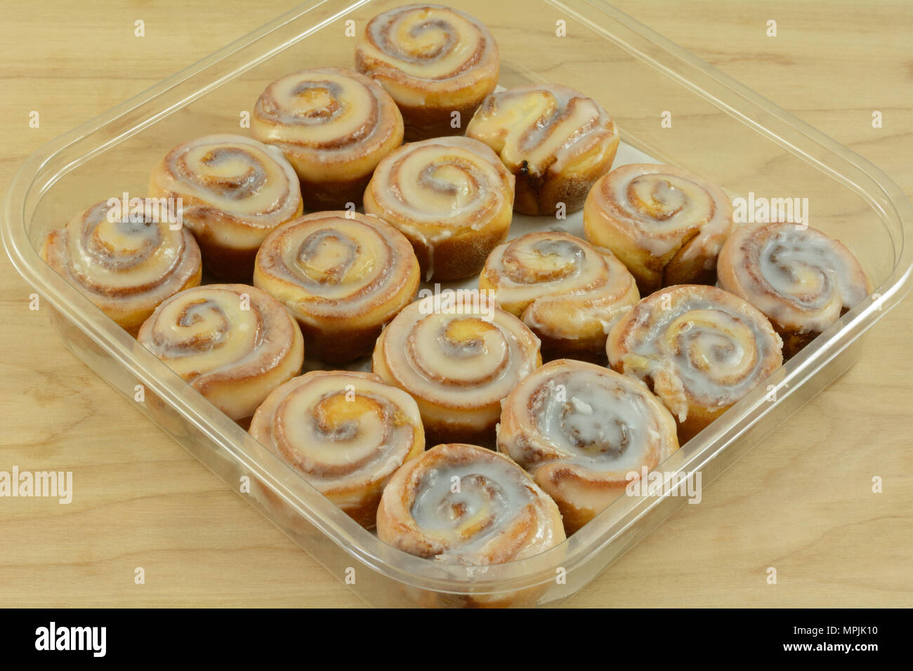 Plastic package of small pinwheel cinnamon rolls with icing freshly ...