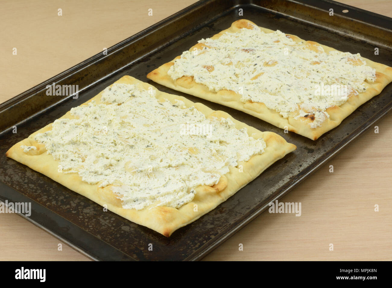 Preparing homemade pizza with ricotta cheese spread on flatbread on ...