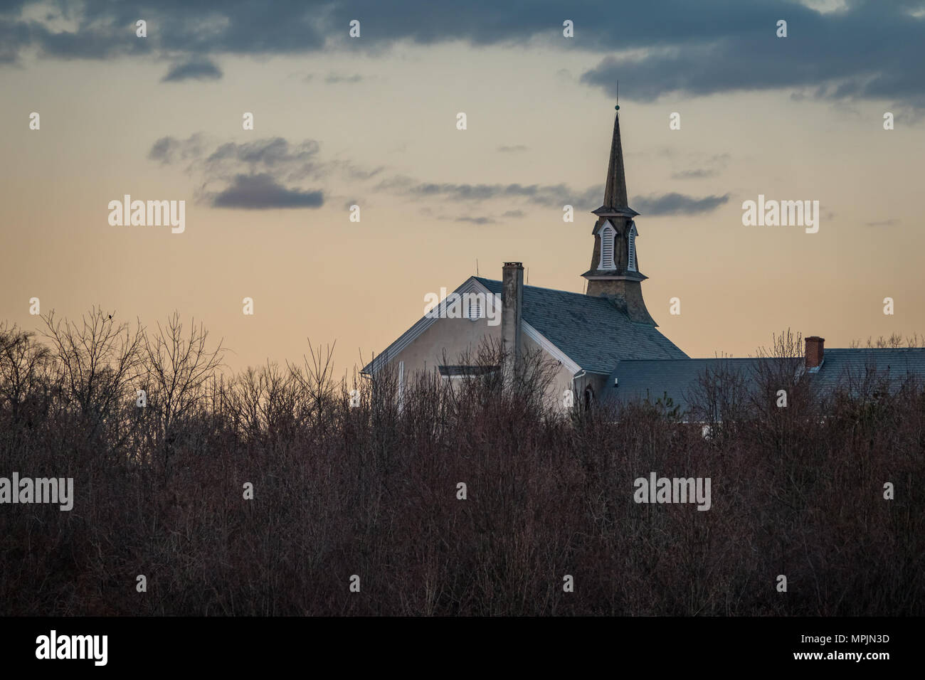 church at sunset viewed from across a field with tall grasses in front ...