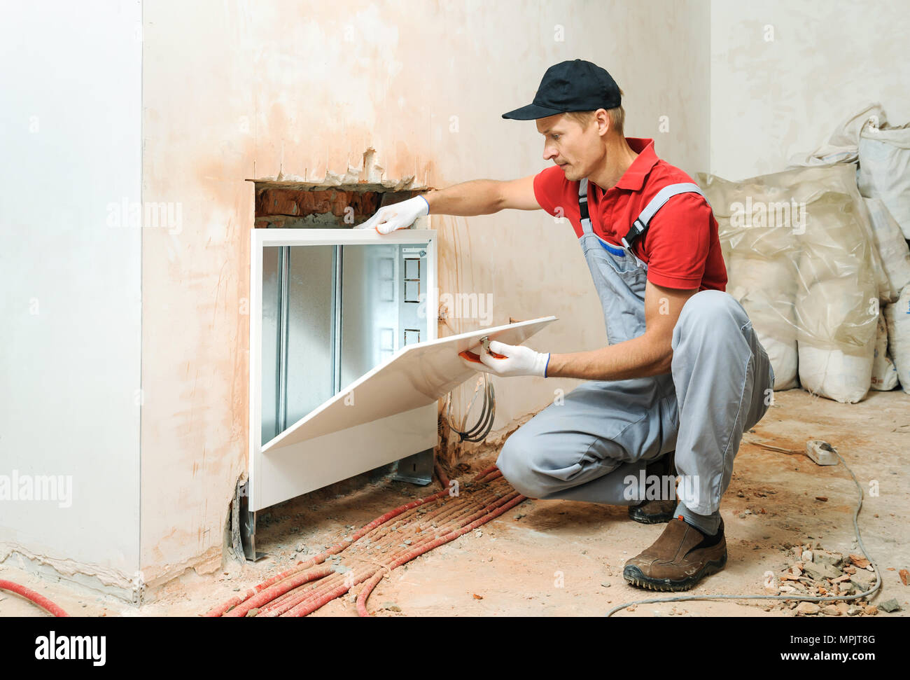 Installation of home heating. Worker installs metal box for ...