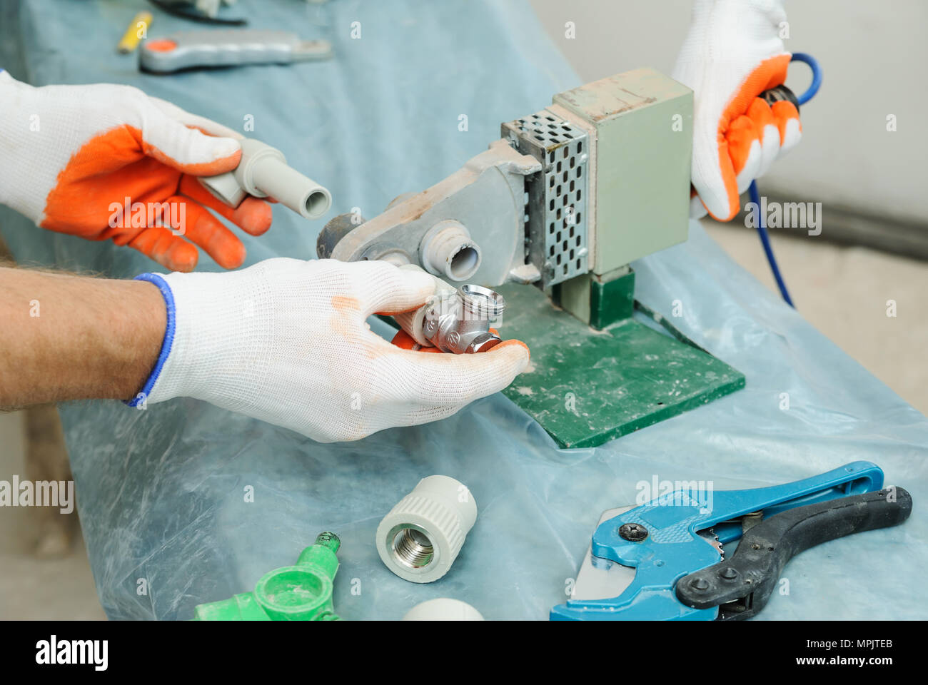 Soldering plastic pipe. A worker heats the pipe and knee for future ...