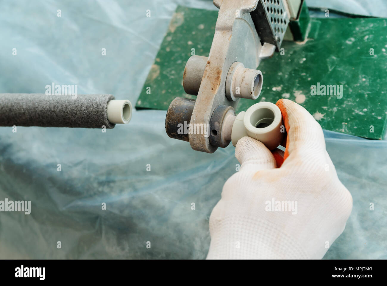 Soldering plastic pipe. A worker heats the pipe and knee for future ...