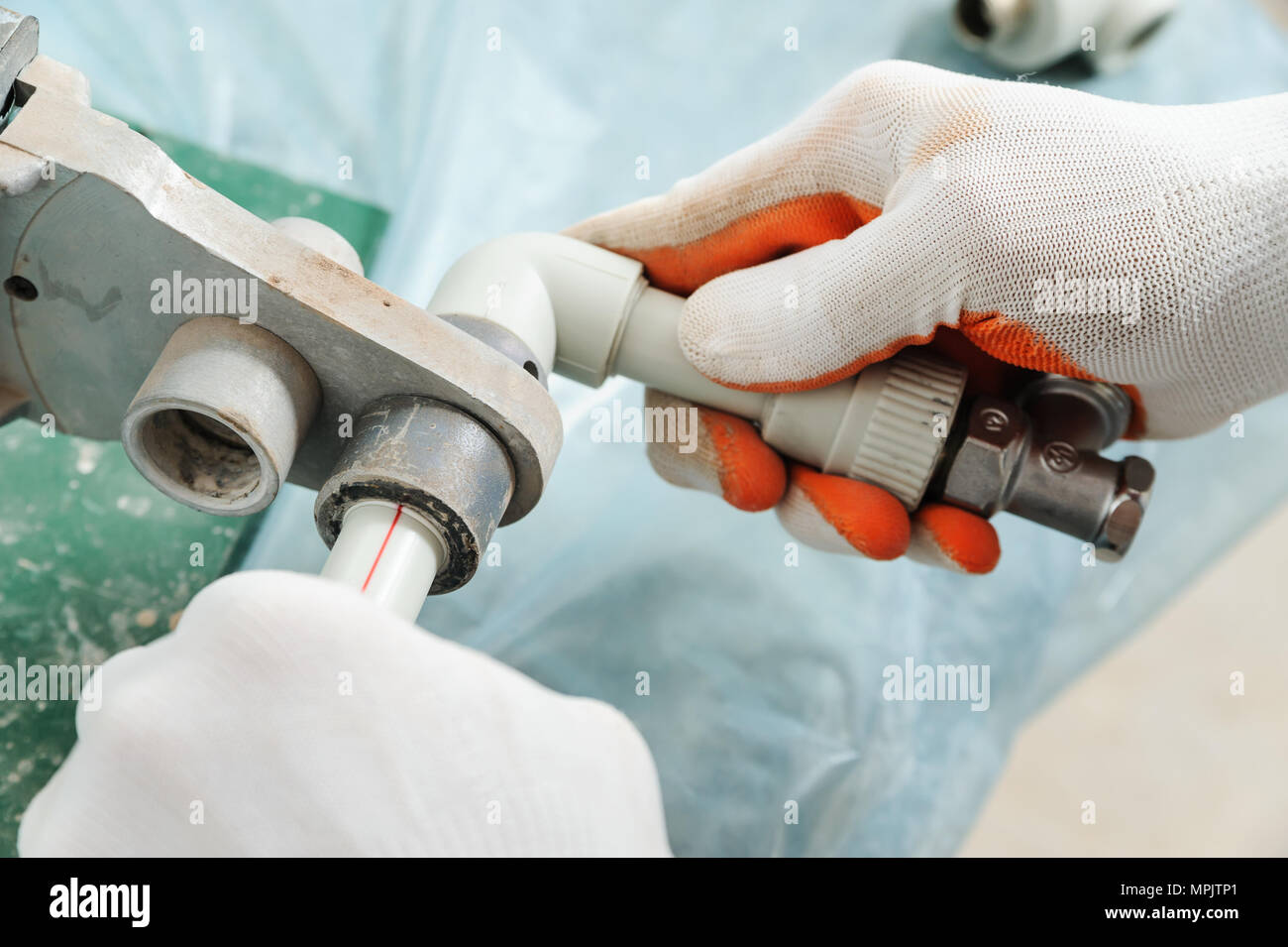 Soldering plastic pipe. A worker heats the pipe and knee for future ...