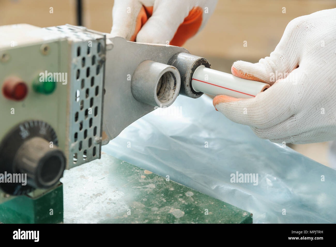 Soldering plastic pipe. A worker heats the pipe and knee for future ...