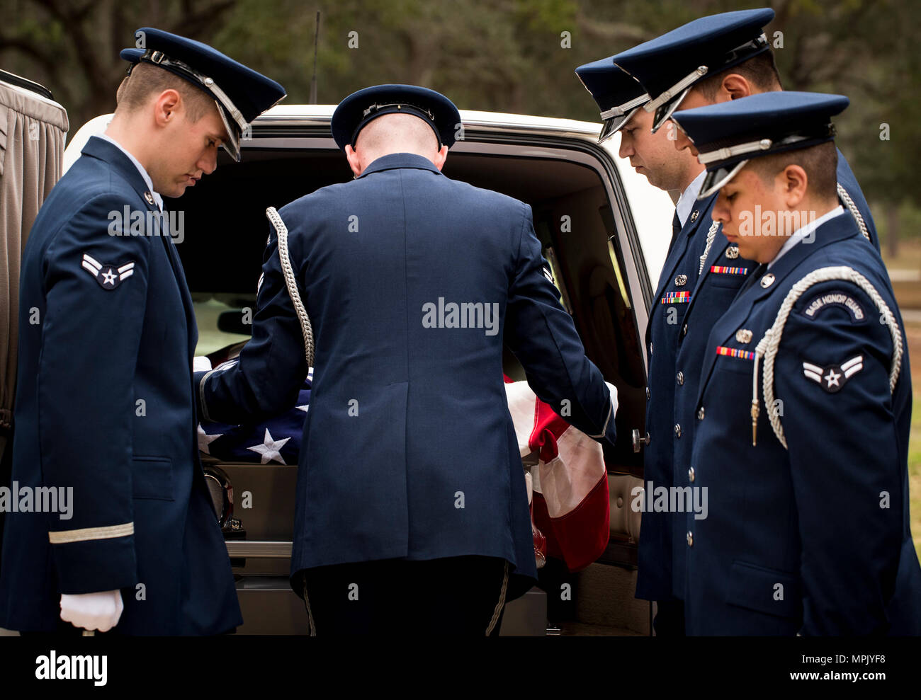 An Honor Guard pall bearer lifts the American flag to begin to remove a ...