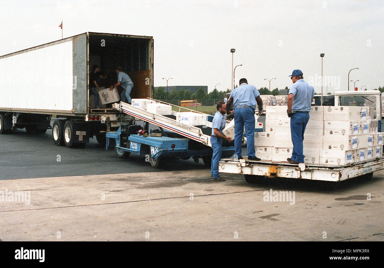MEN LOADING PACKAGES OFF A TRUCK UNTO A LOADING CRATE Stock Photo - Alamy