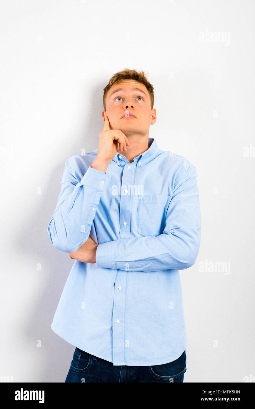 Young man looking up and standing against white wall Stock Photo - Alamy