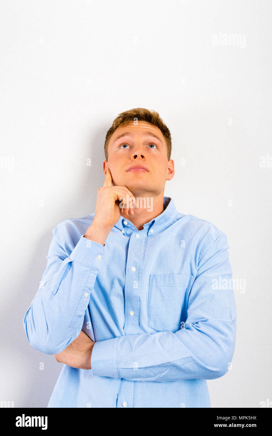 Young man looking up and standing against white wall Stock Photo - Alamy