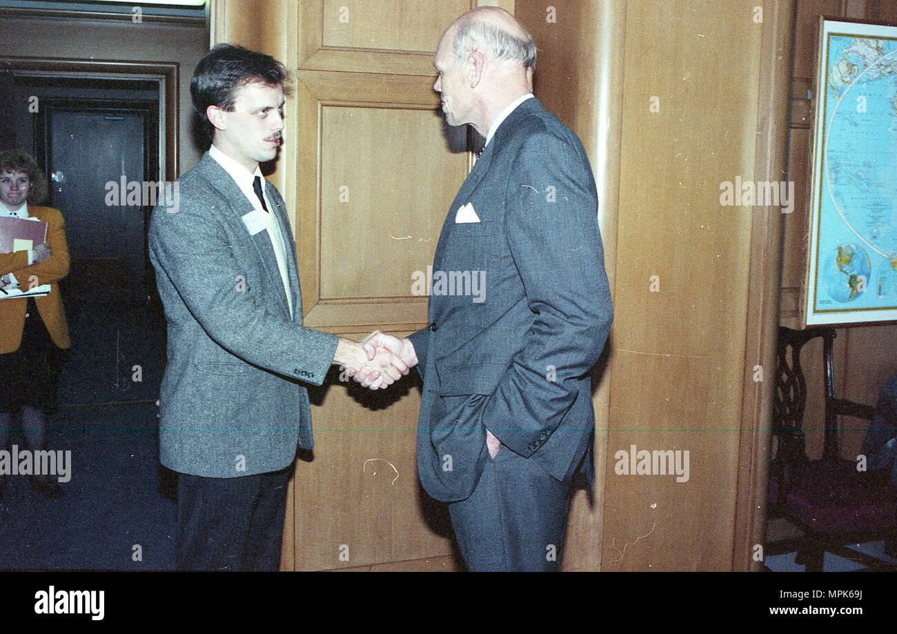TWO MEN GREETING EACH OTHER WITH A HAND SHACK WITH A WOMAN WATCHING IN ...