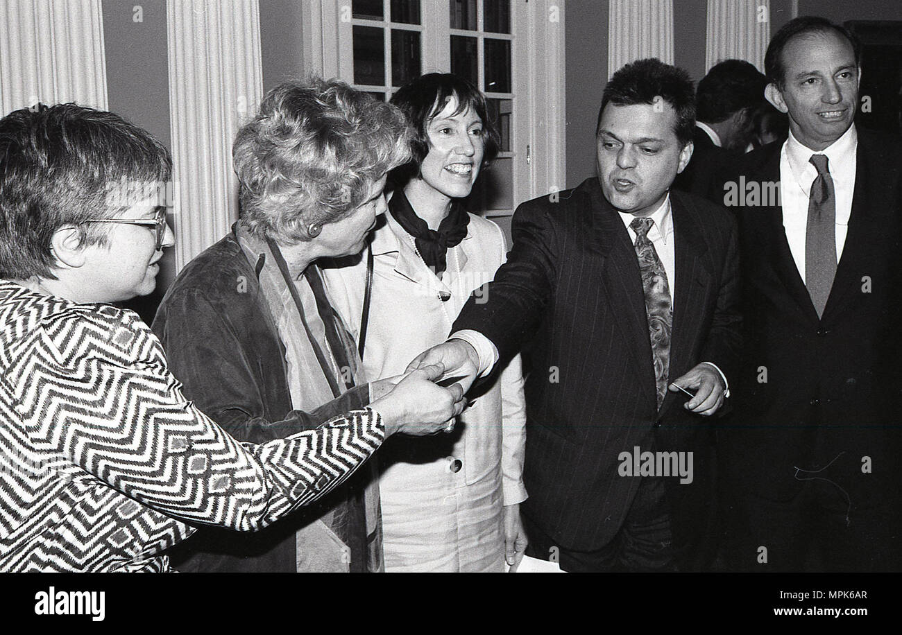 THERE ARE A GROUP OF MEN AND WOMEN GATHERING AROUND AT A BUSINESS ...