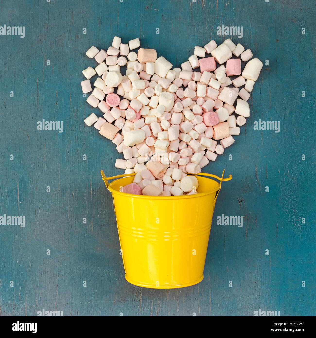 bunch of marshmallow laid out in the shape of a heart over a yellow ...