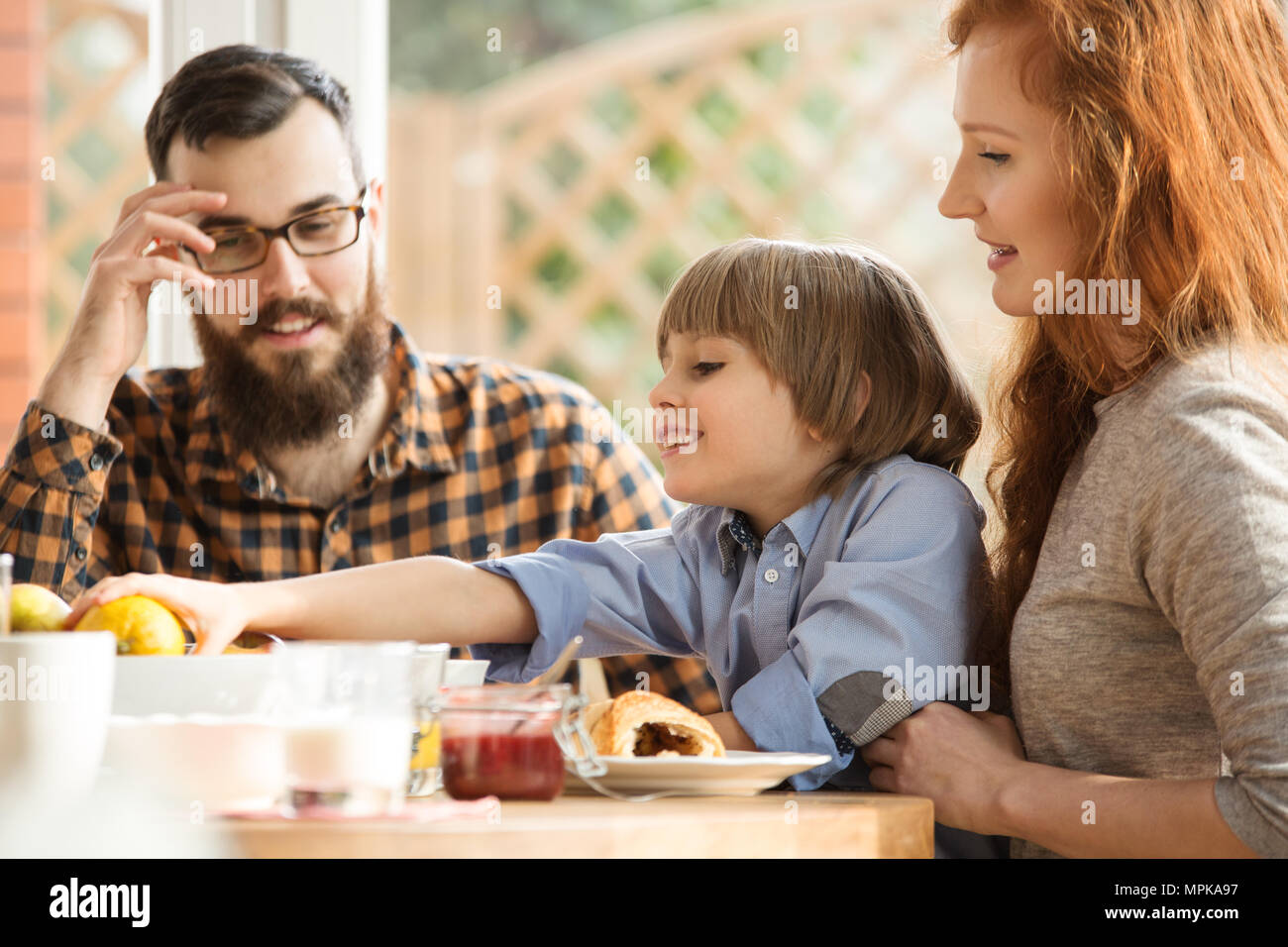 Happy family eating breakfast. Smiling son sitting with mother and ...