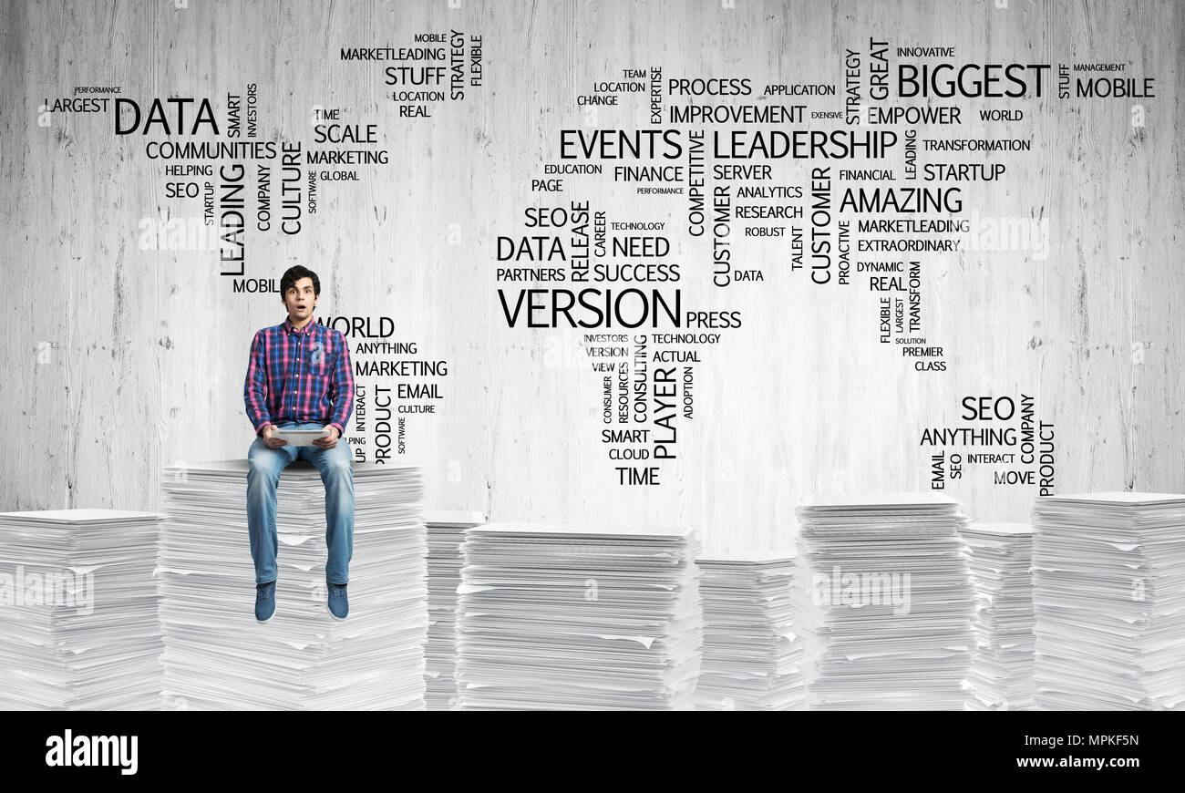 Attractive man sitting on pile of paper documents Stock Photo - Alamy