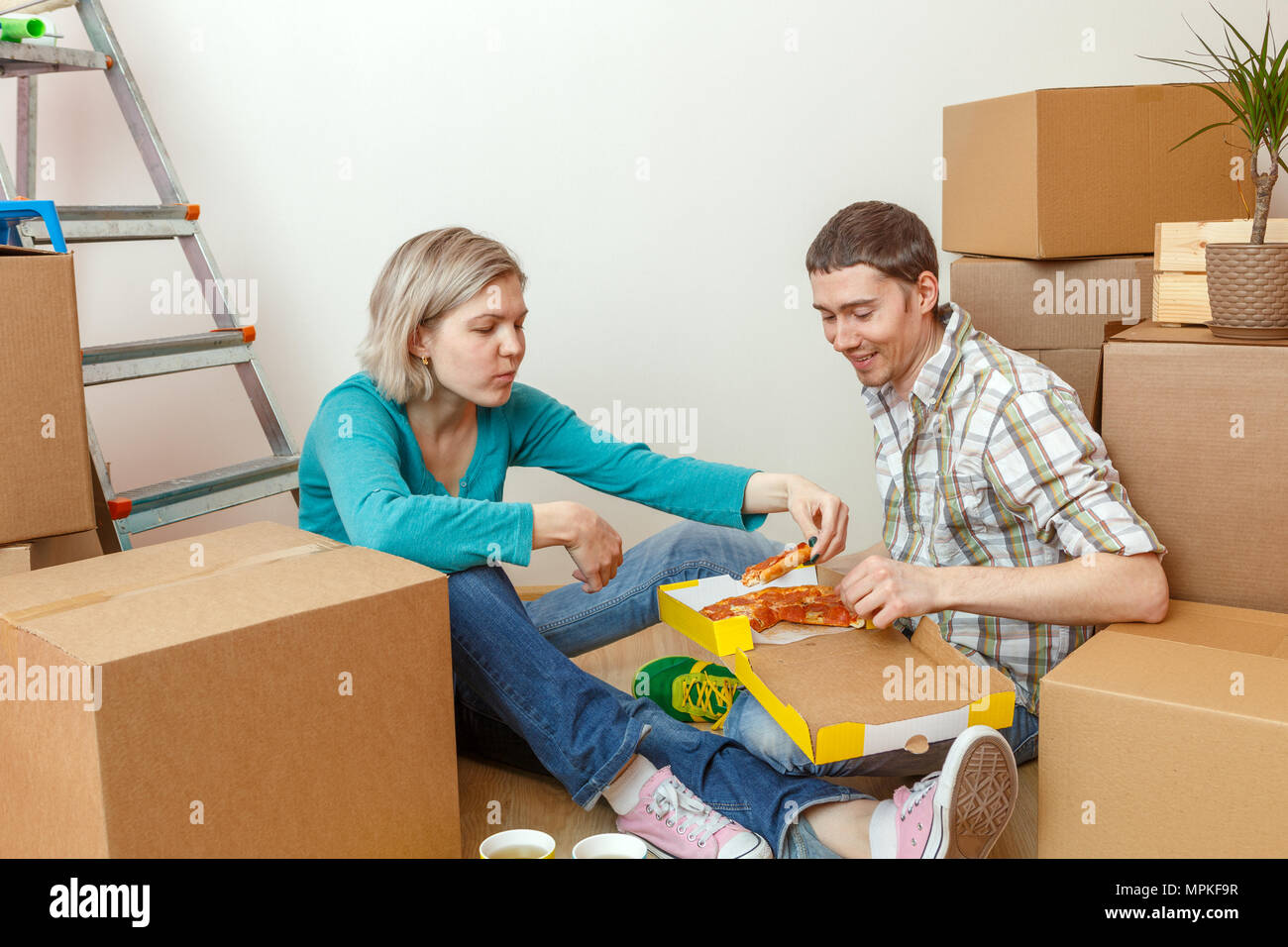 Photos of women and men eating pizza among cardboard boxes Stock Photo ...