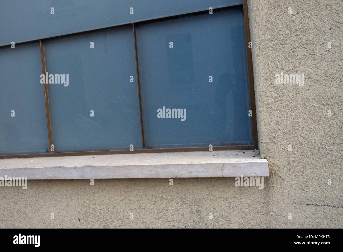 Beveled windows of the metal frame on the beige wall, the blue sky is ...