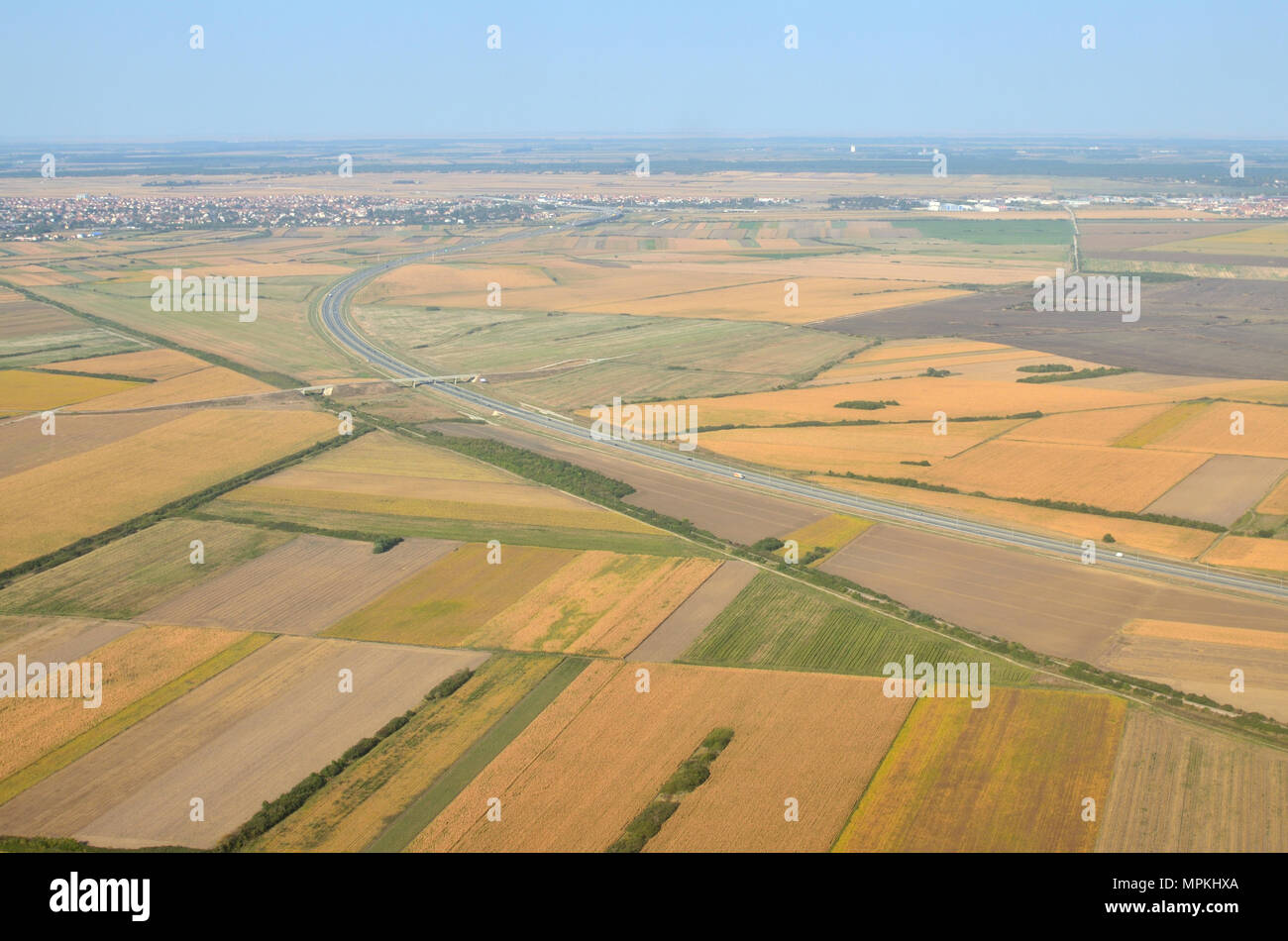 Plains with different crops and plants, highway and a city suburb seen ...