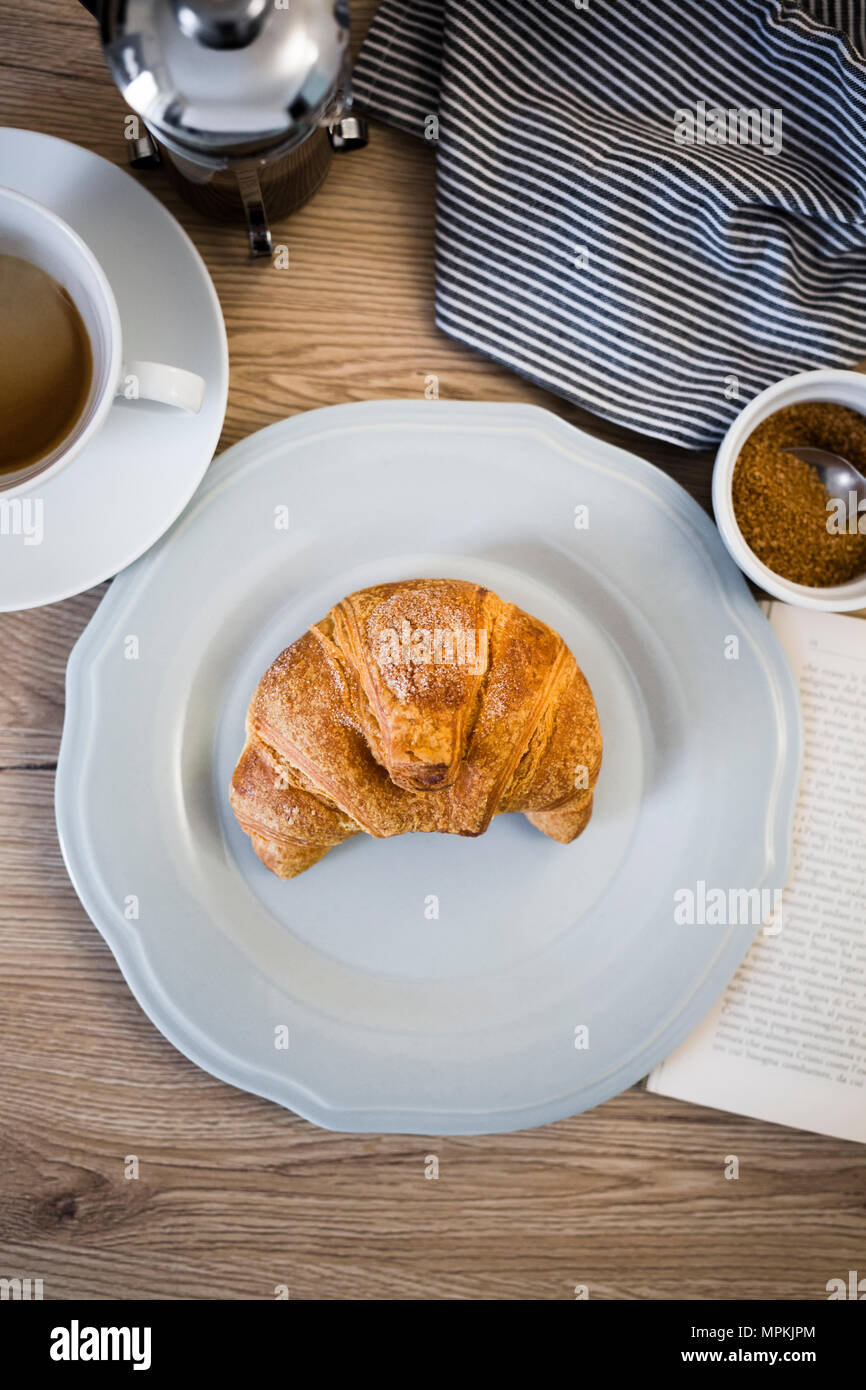 Italian cornetto on plate, book, serviette and coffee cup Stock Photo ...