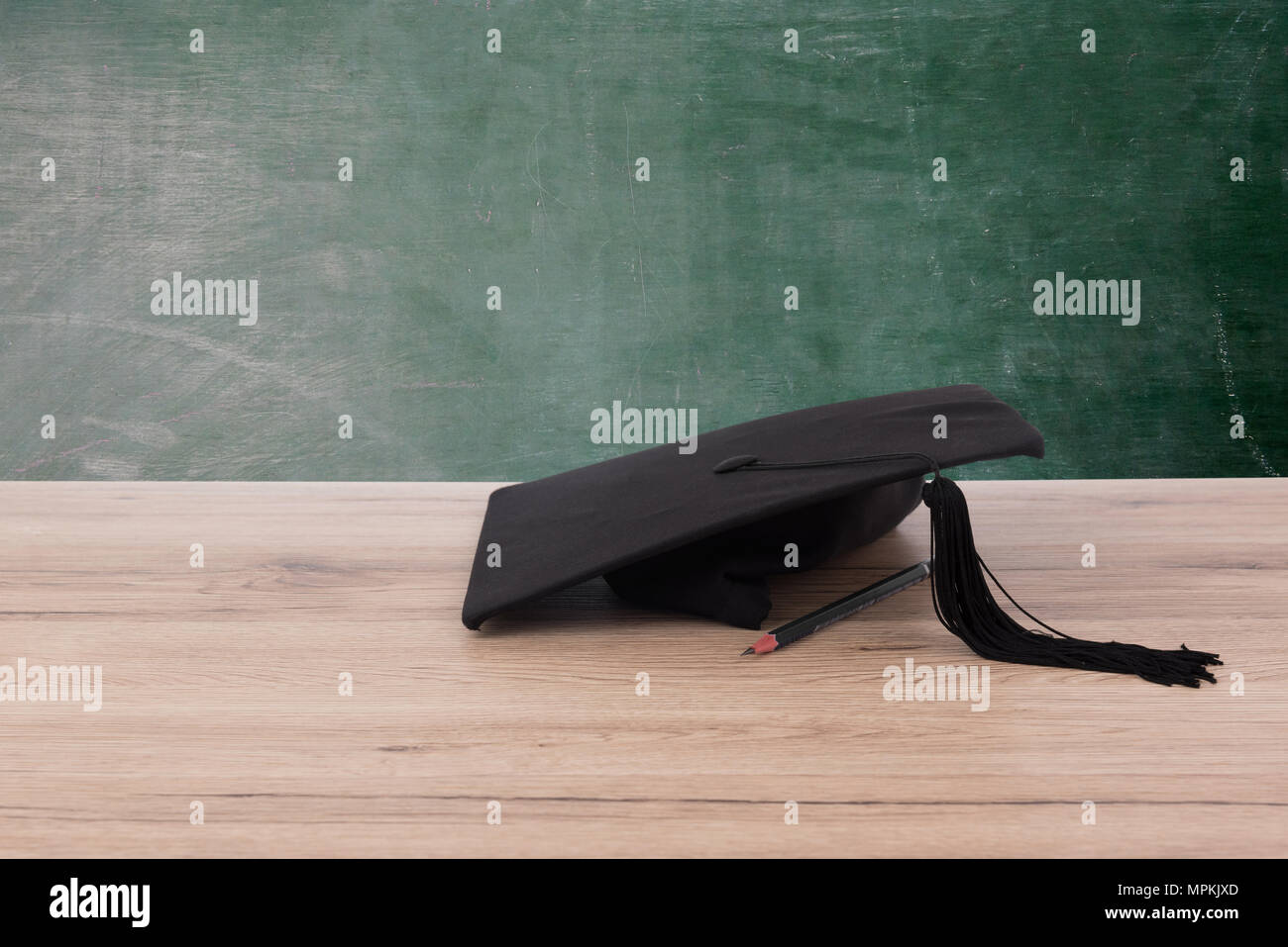 Graduated cap placed on a wooden desk in the classroom Stock Photo - Alamy