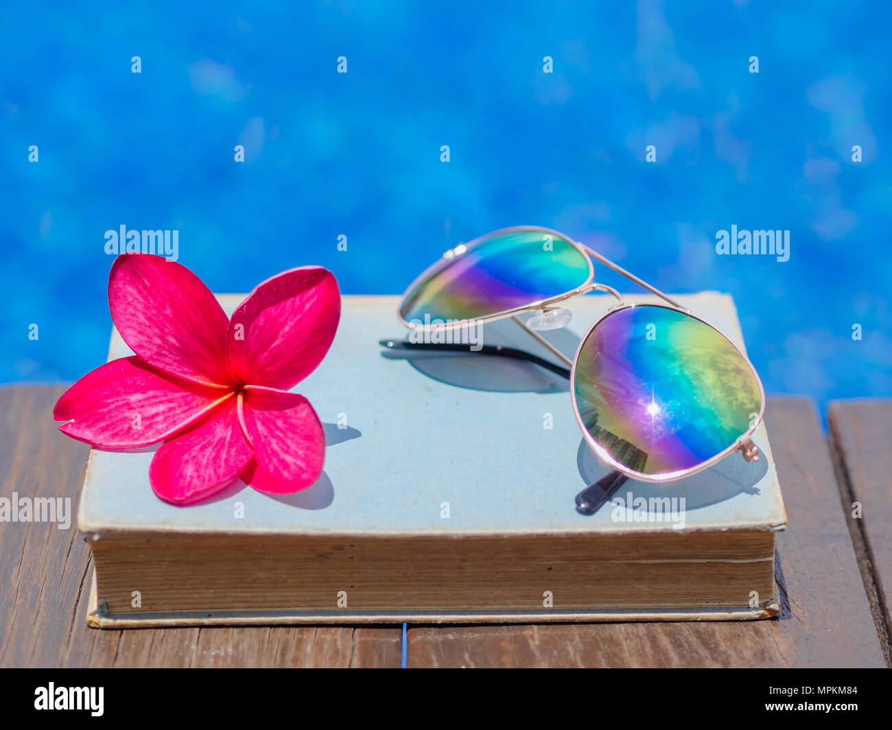 Book and sunglasses, blue water background, summer and tropical travel ...