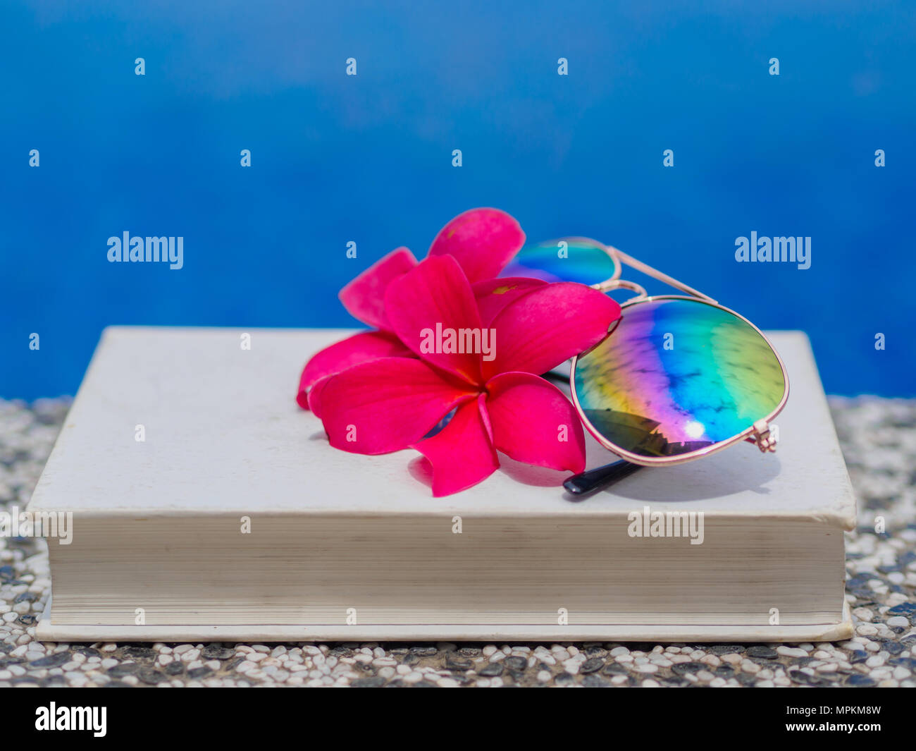 Book and sunglasses, blue water background, summer and tropical travel ...