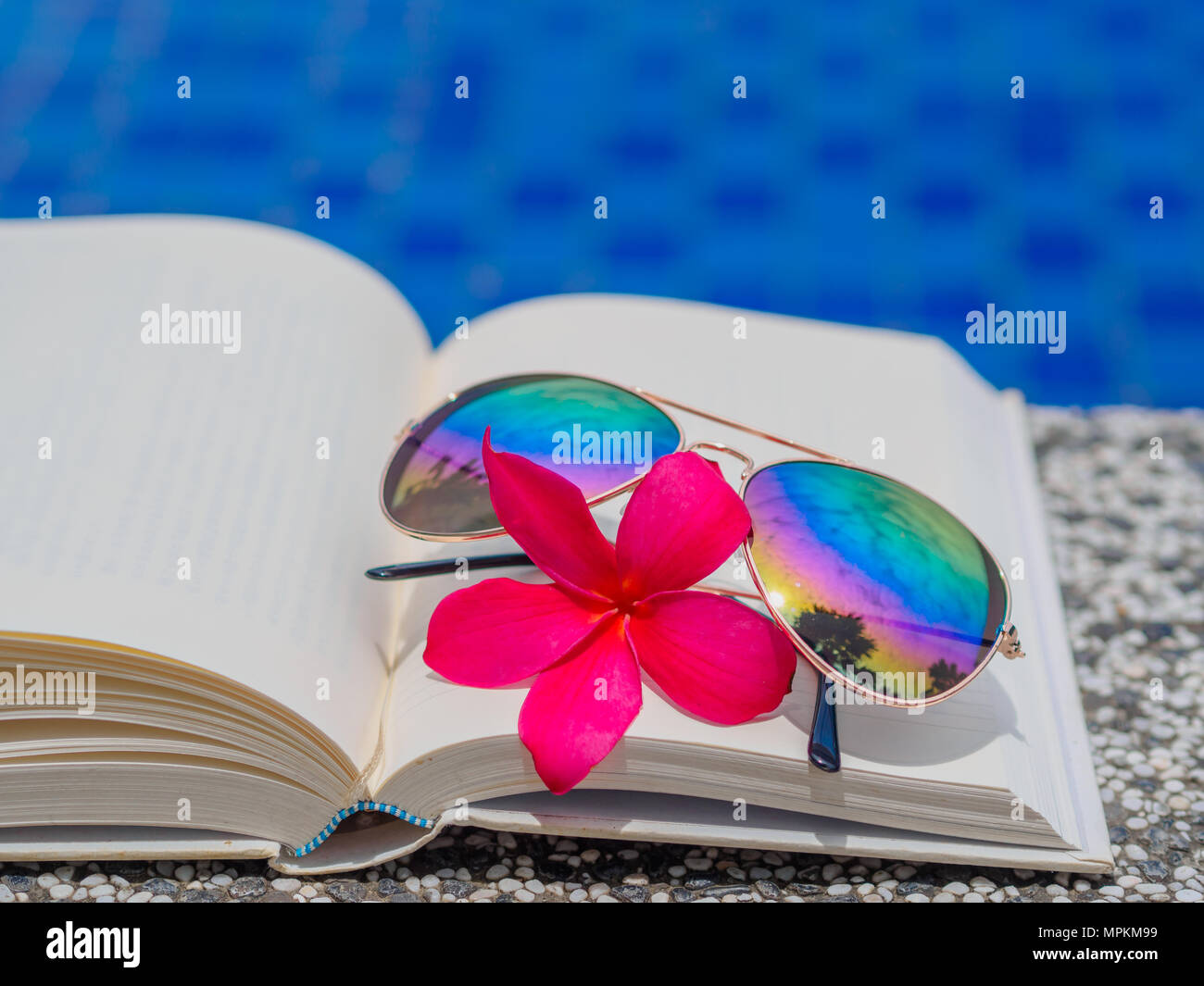 Book and sunglasses, blue water background, summer and tropical travel ...