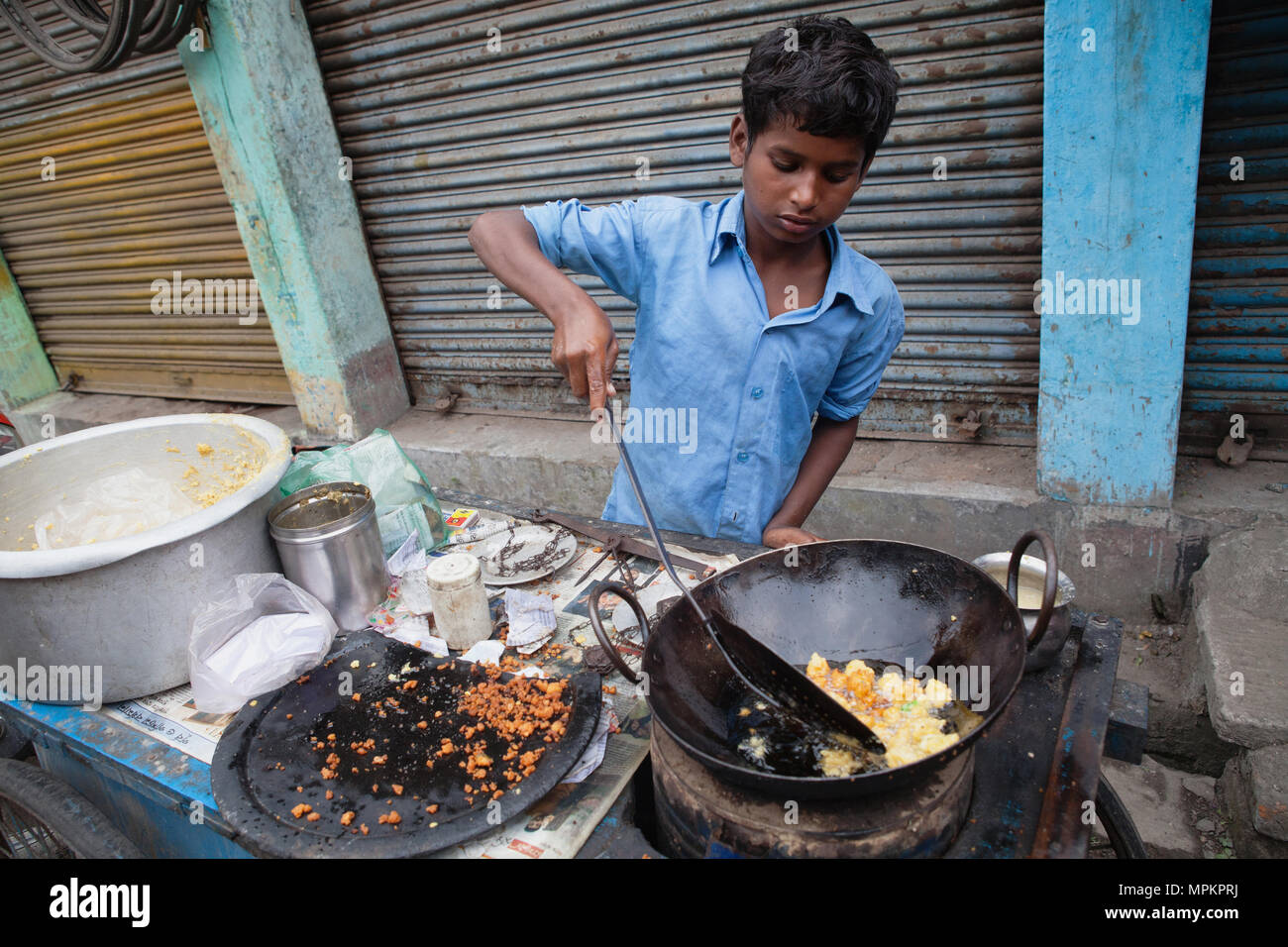 India, West Bengal, Asansol, A boy fries chilli pakora on a street food ...
