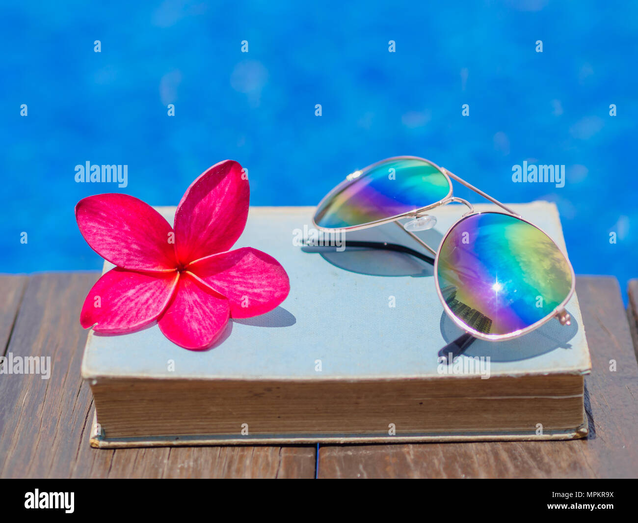 Book and sunglasses, blue water background, summer and tropical travel ...