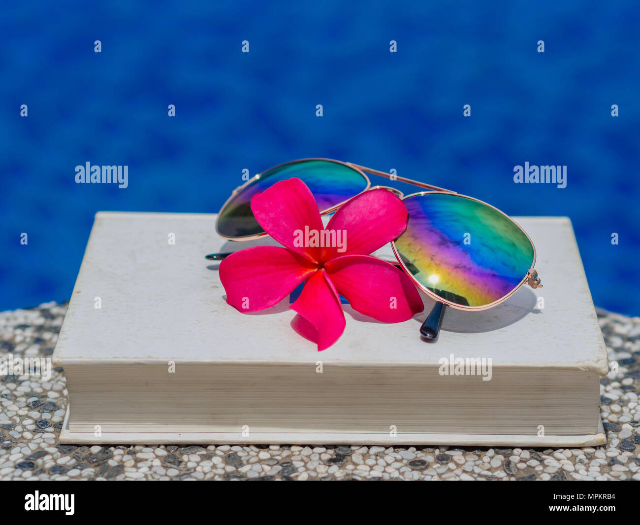 Book and sunglasses, blue water background, summer and tropical travel ...