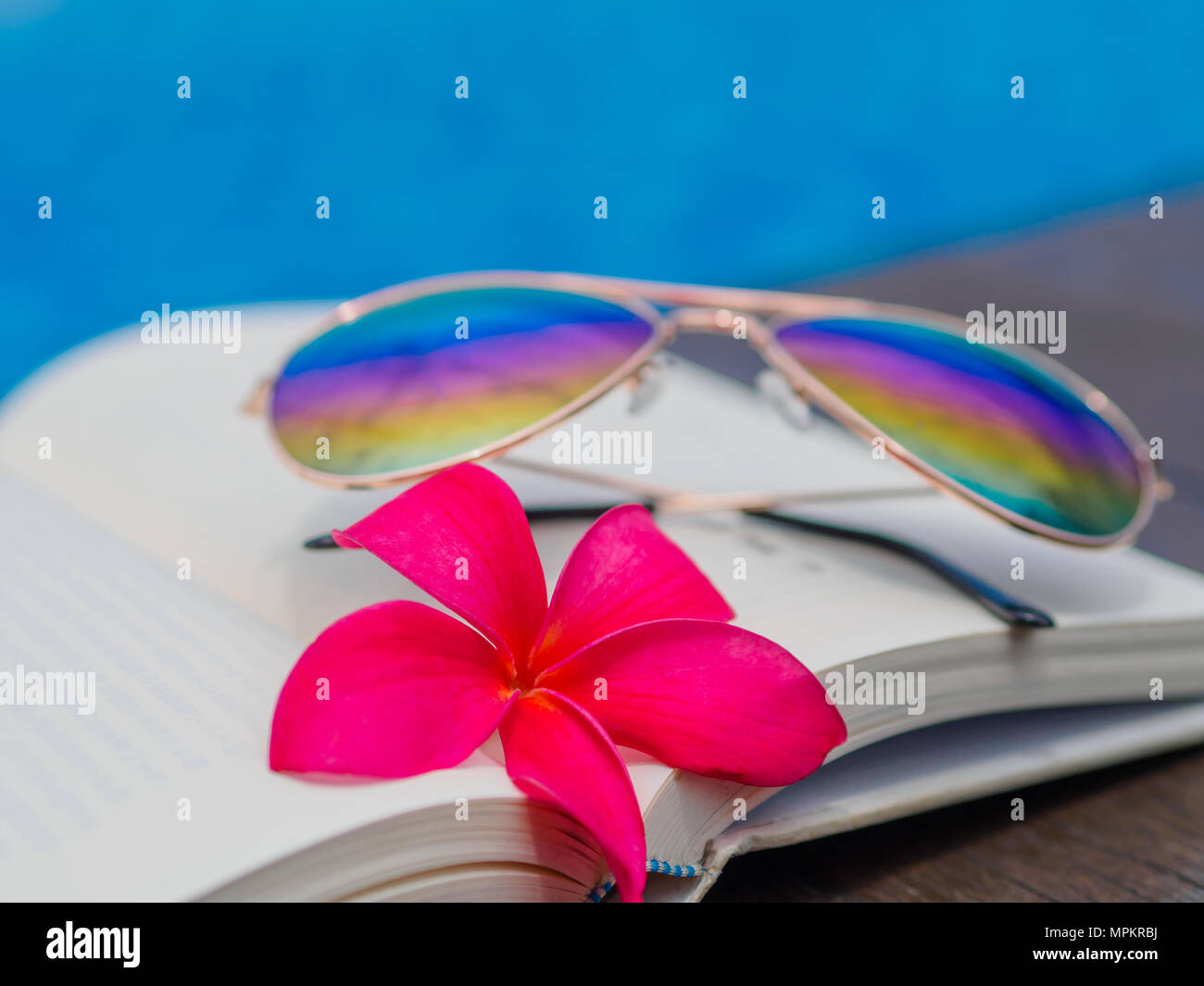 Book and sunglasses, blue water background, summer and tropical travel ...