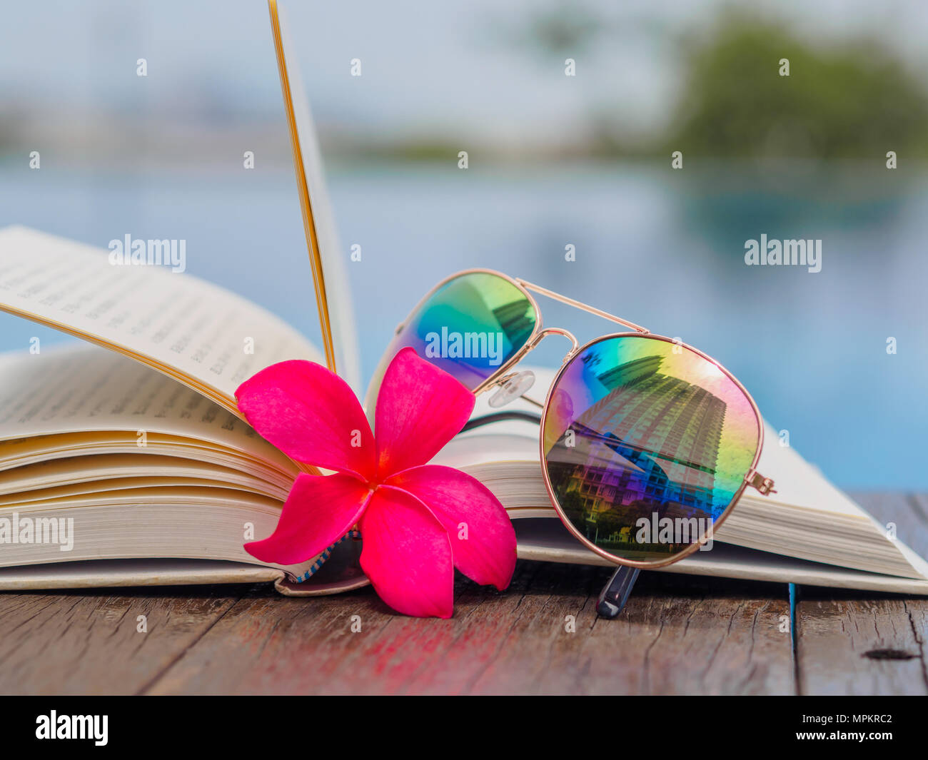 Book and sunglasses, blue water background, summer and tropical travel ...