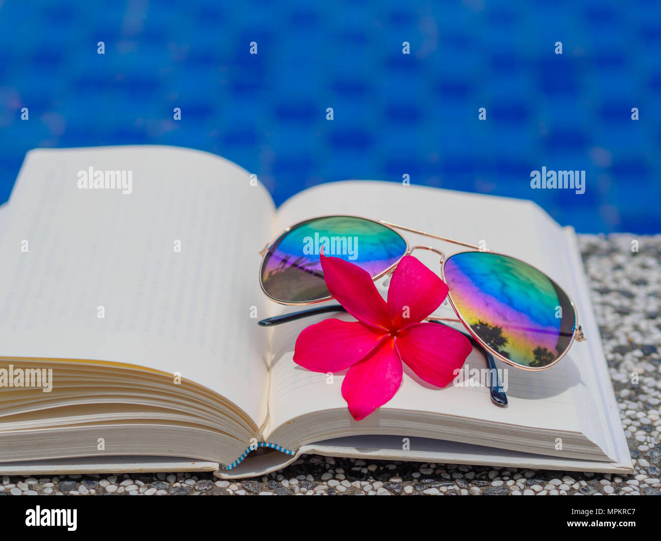 Book and sunglasses, blue water background, summer and tropical travel ...