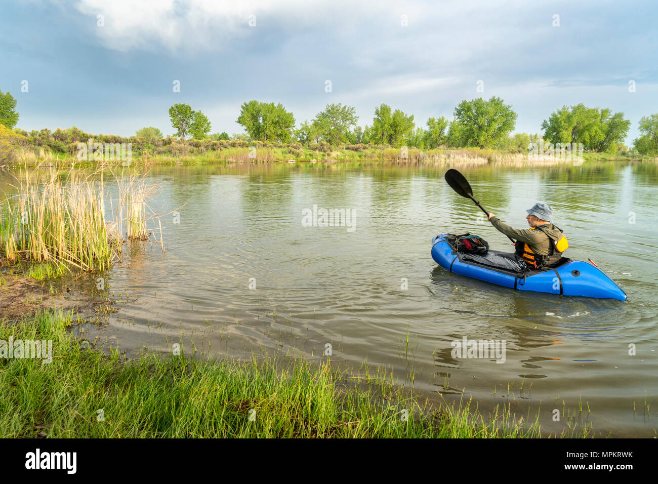 a senior male paddling a blue pacraft (one-person light raft used for ...