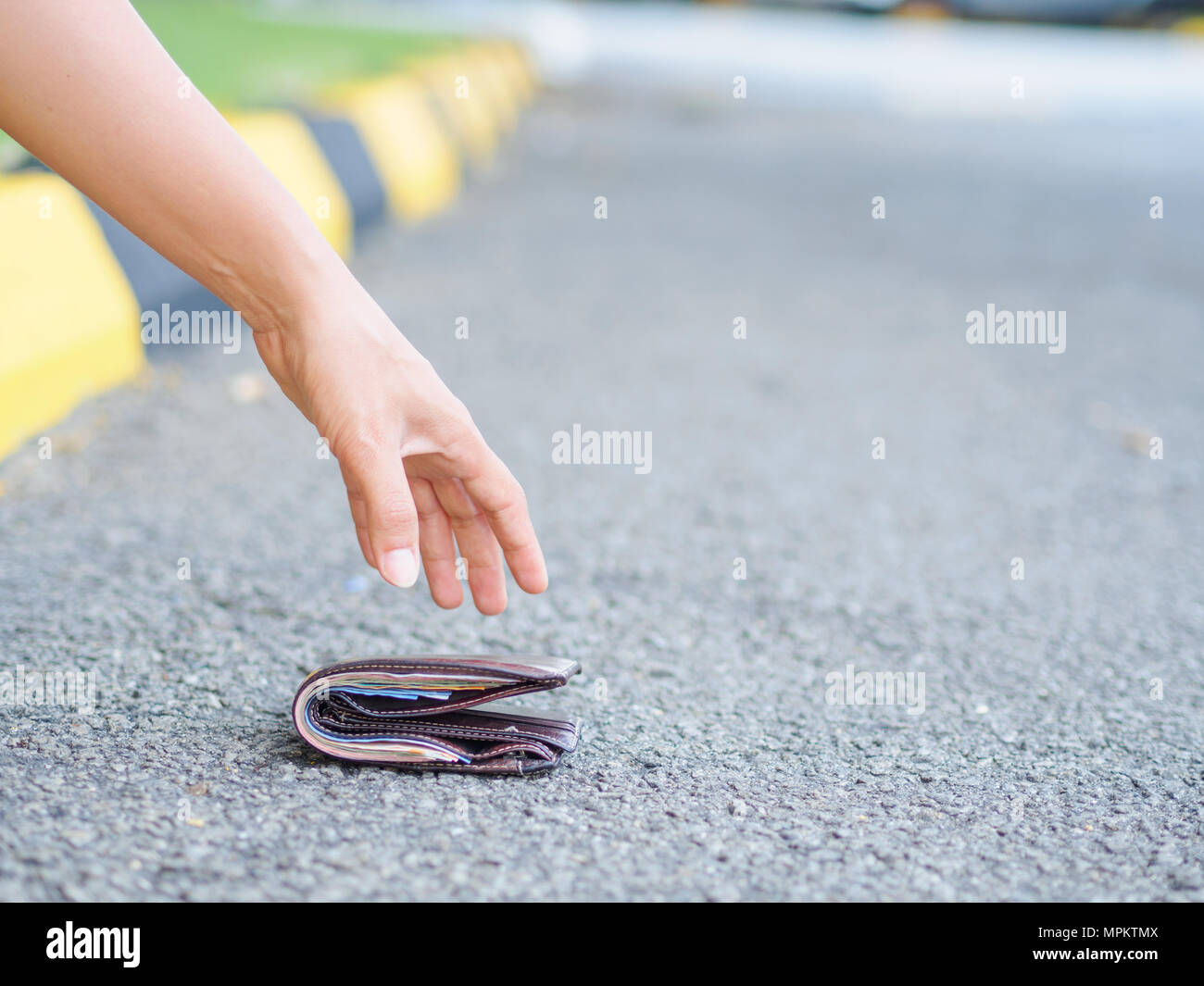 Close-up Of A Woman Picking Up Fallen Wallet On road side Stock Photo ...