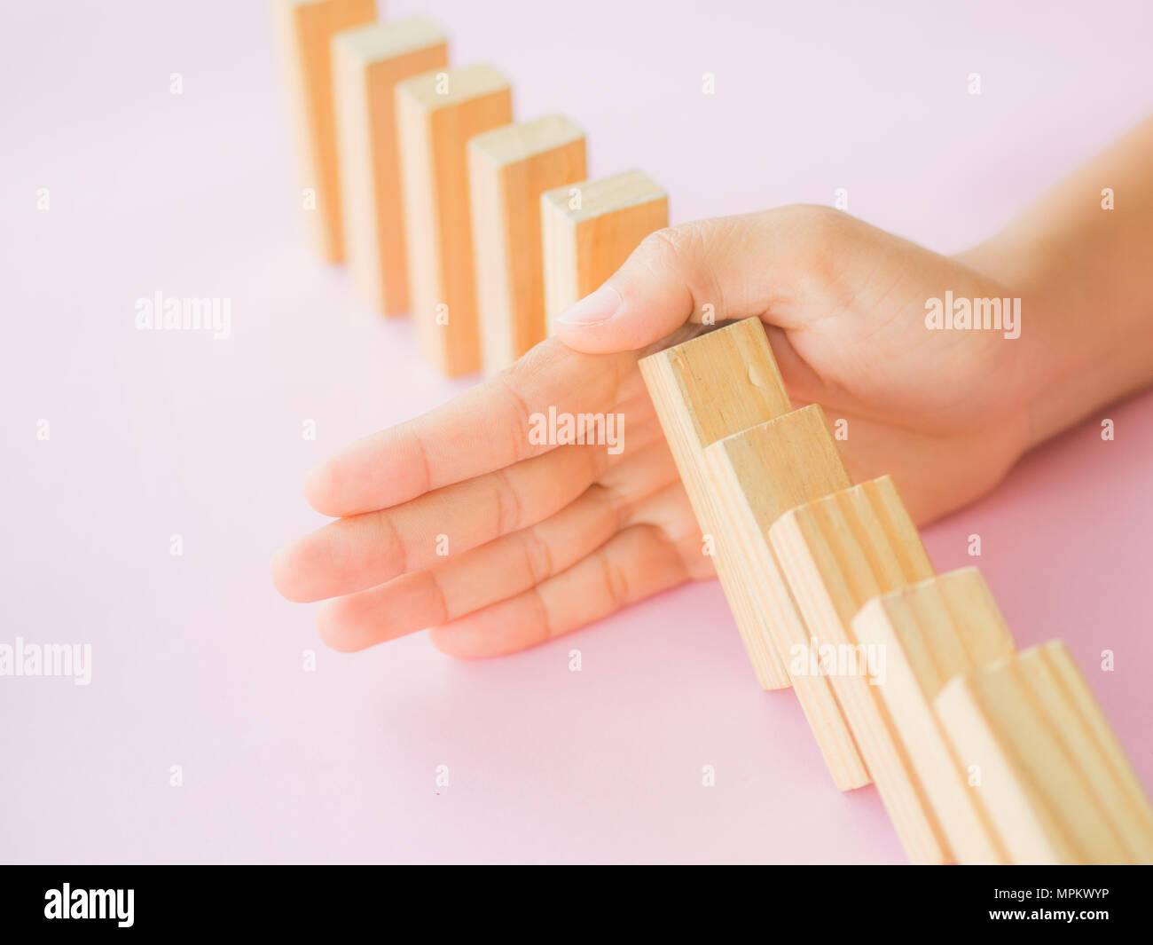 Solution concept with hand stopping wooden blocks from falling in the ...