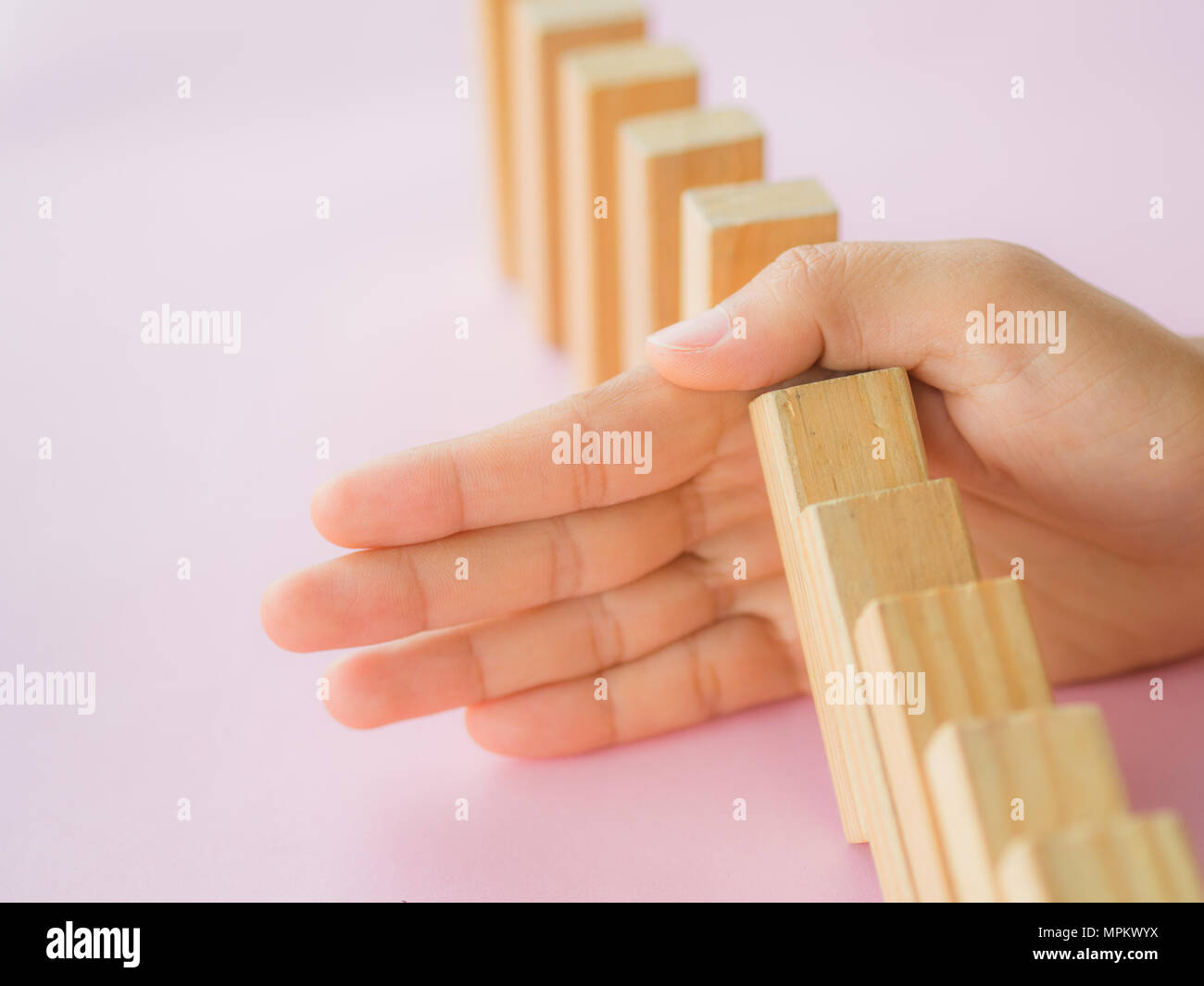 Solution concept with hand stopping wooden blocks from falling in the ...