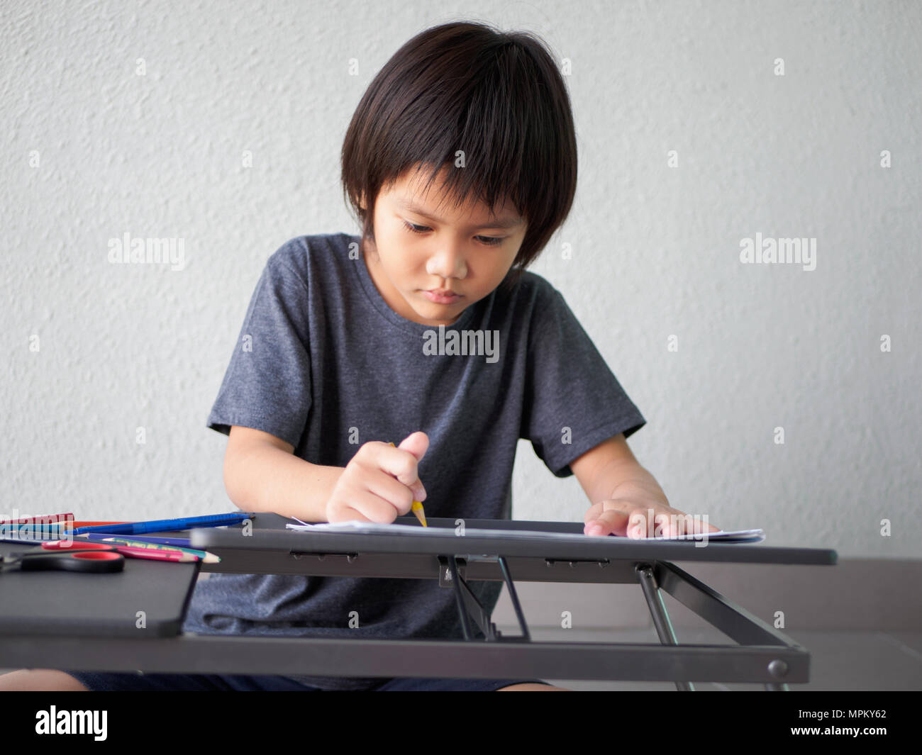 Portrait of cute happy preschool kid boy at home making homework ...