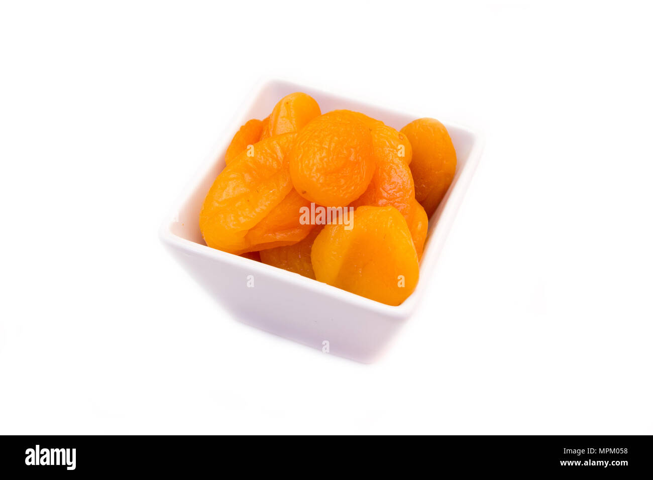 Pitted apricots on square bowl on a white background Stock Photo - Alamy