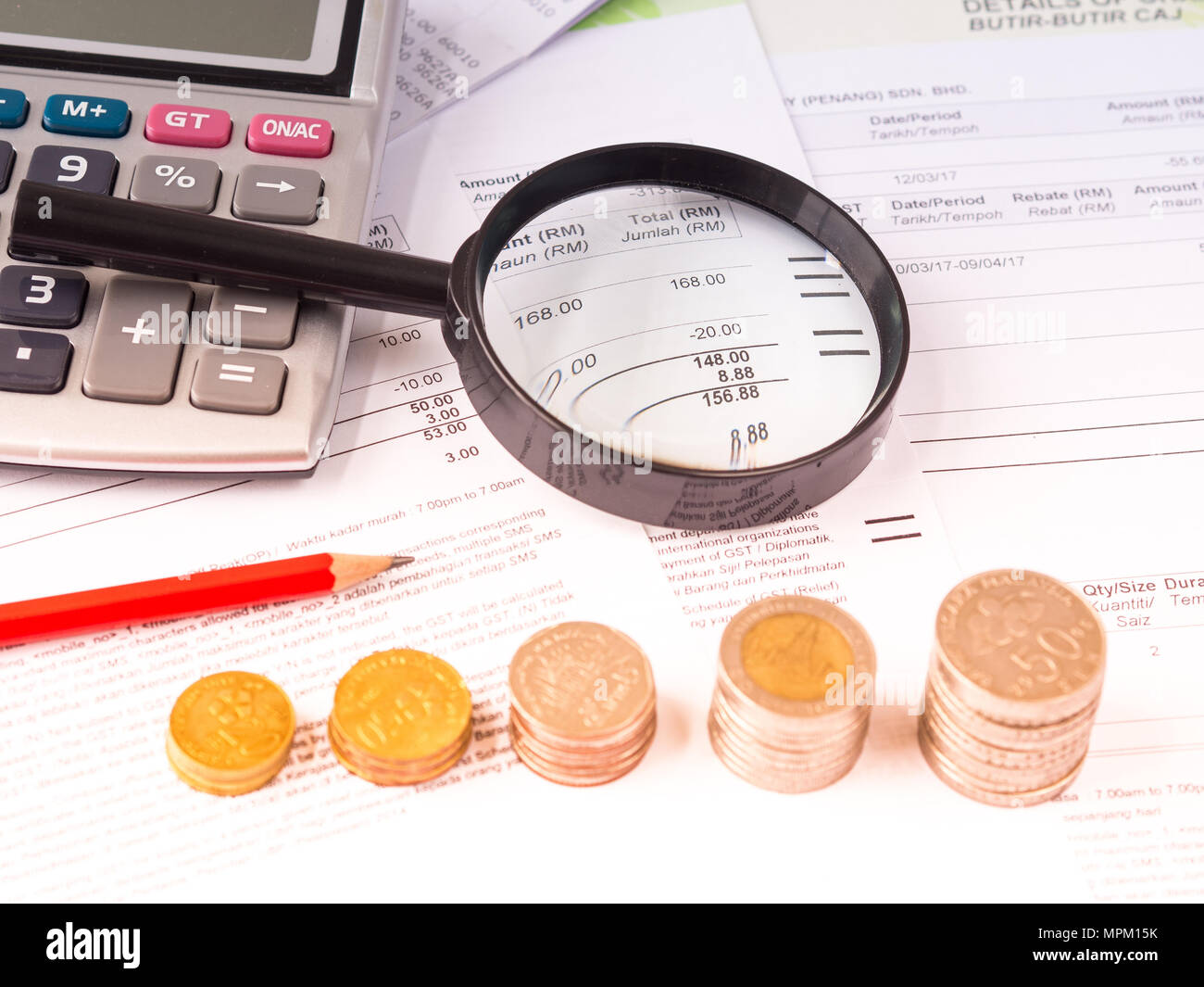 Magnifying glass on financial statement with calculator and stack of ...