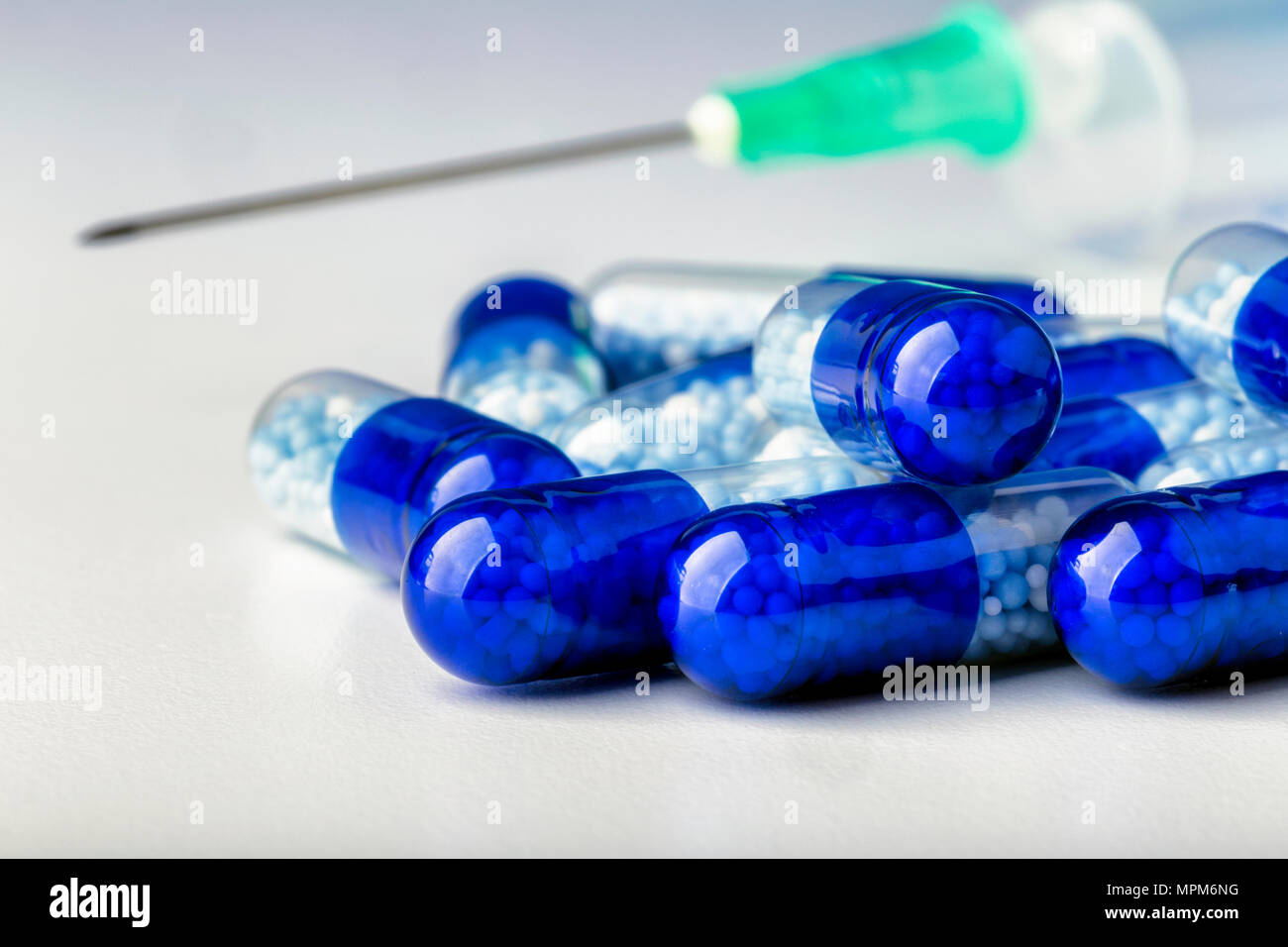 Bunch of blue pills with green injection in the background. Medical ...