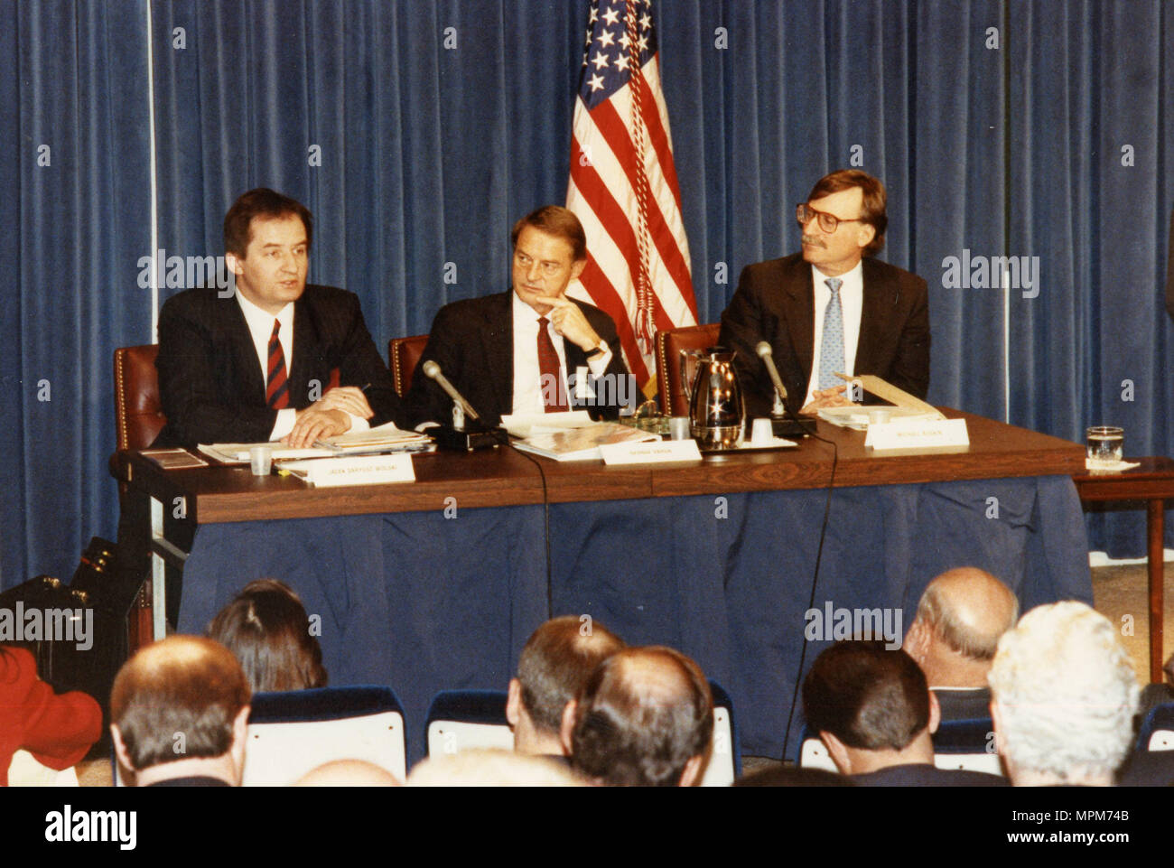 THREE MEN AT THE TABLE ARE HAVING A CONVERSATION WITH A GROUP OF MEN ...