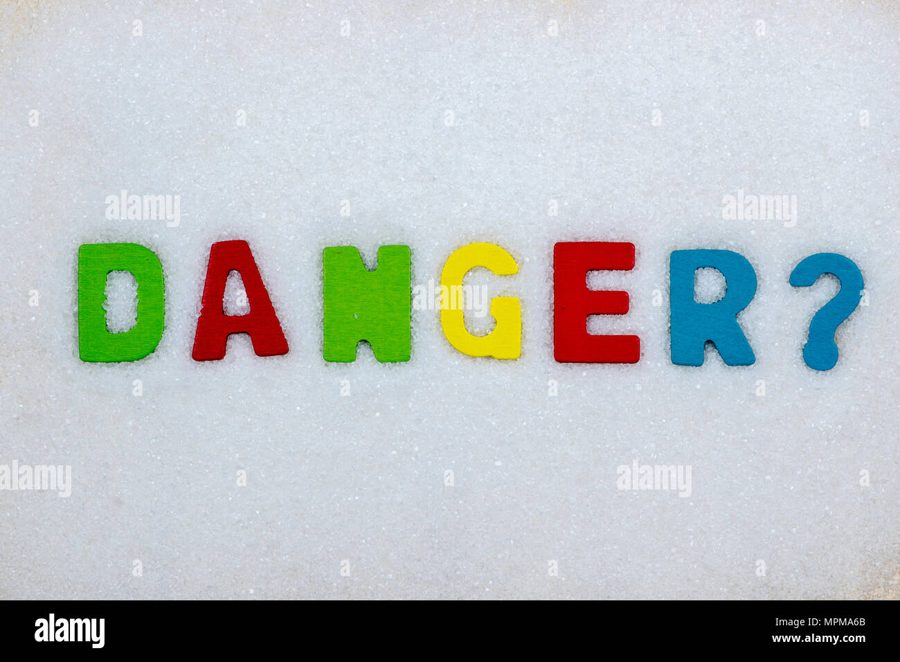 "Danger?" Colorful text and letters in wood on white sugar crystals ...