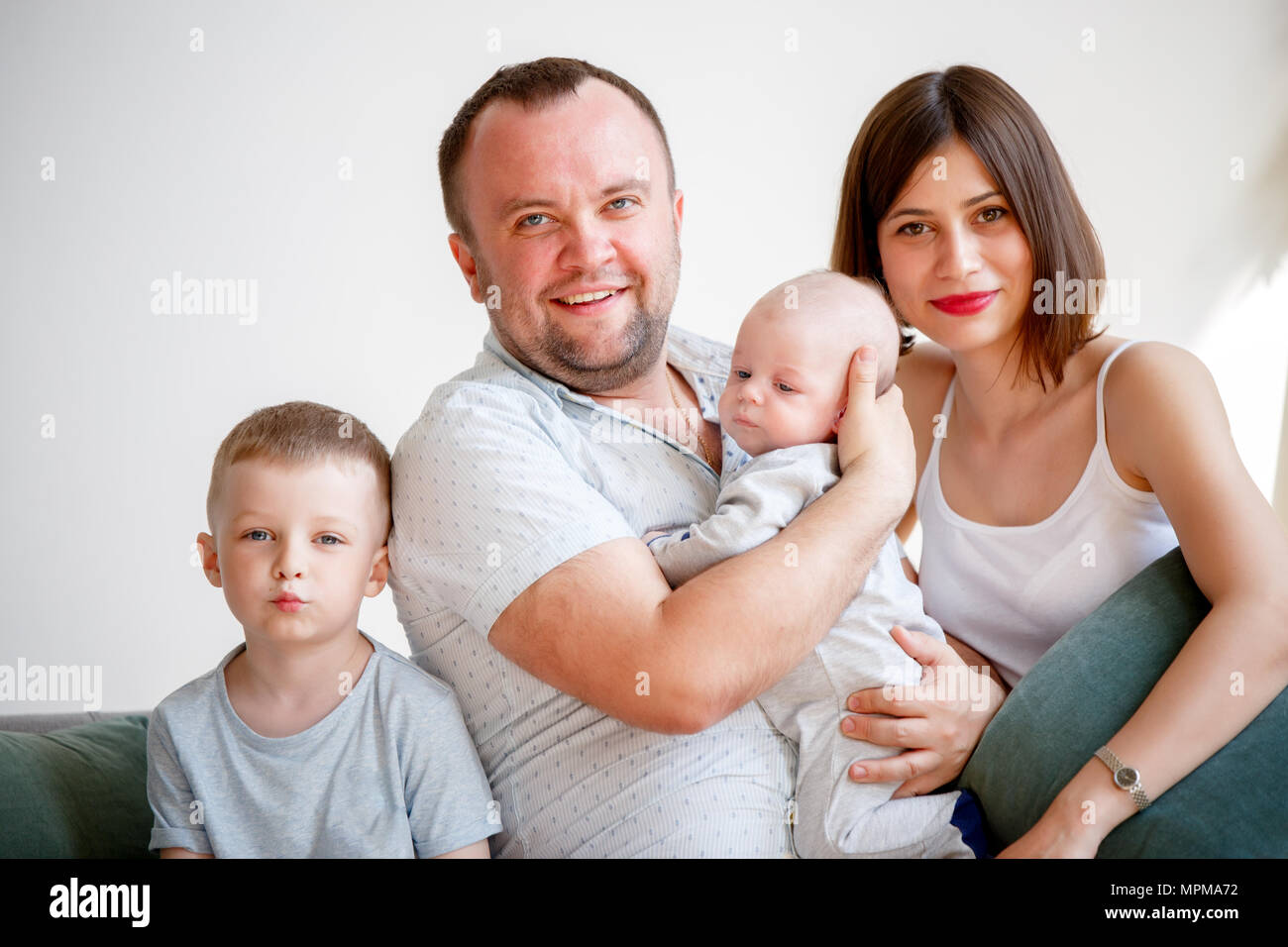 Photo of couple with two young sons sitting on sofa Stock Photo - Alamy