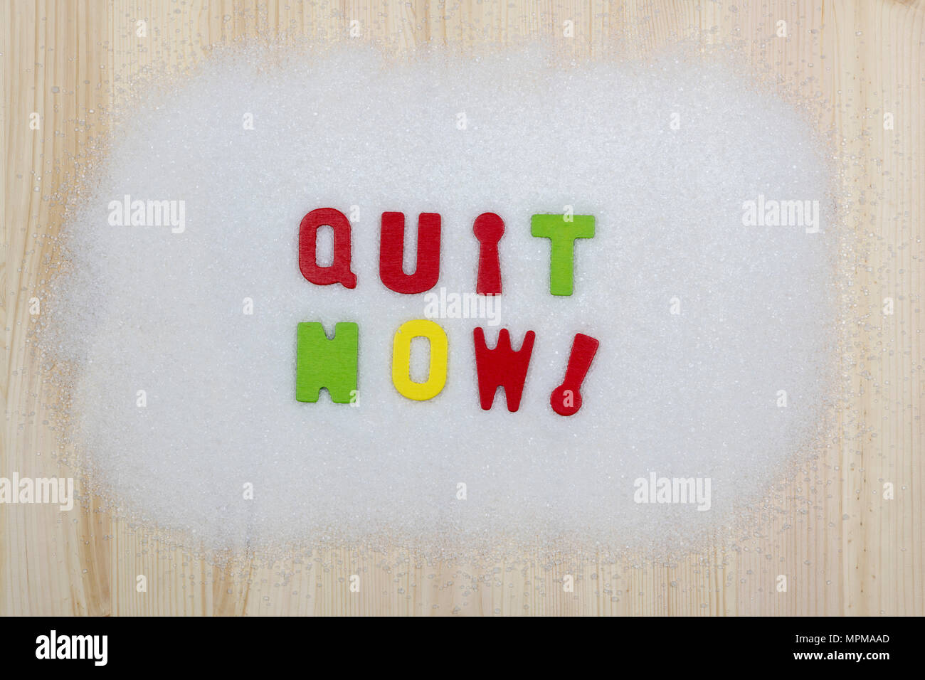 "Quit now!" Colorful text and letters in wood on white sugar crystals ...