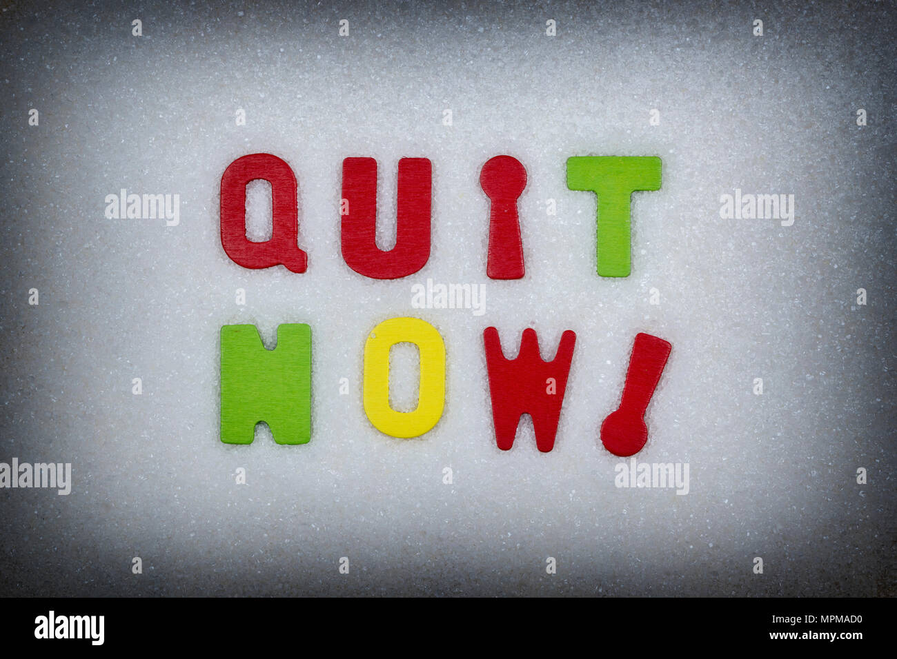 "Quit now!" Colorful text and letters in wood on white sugar crystals ...