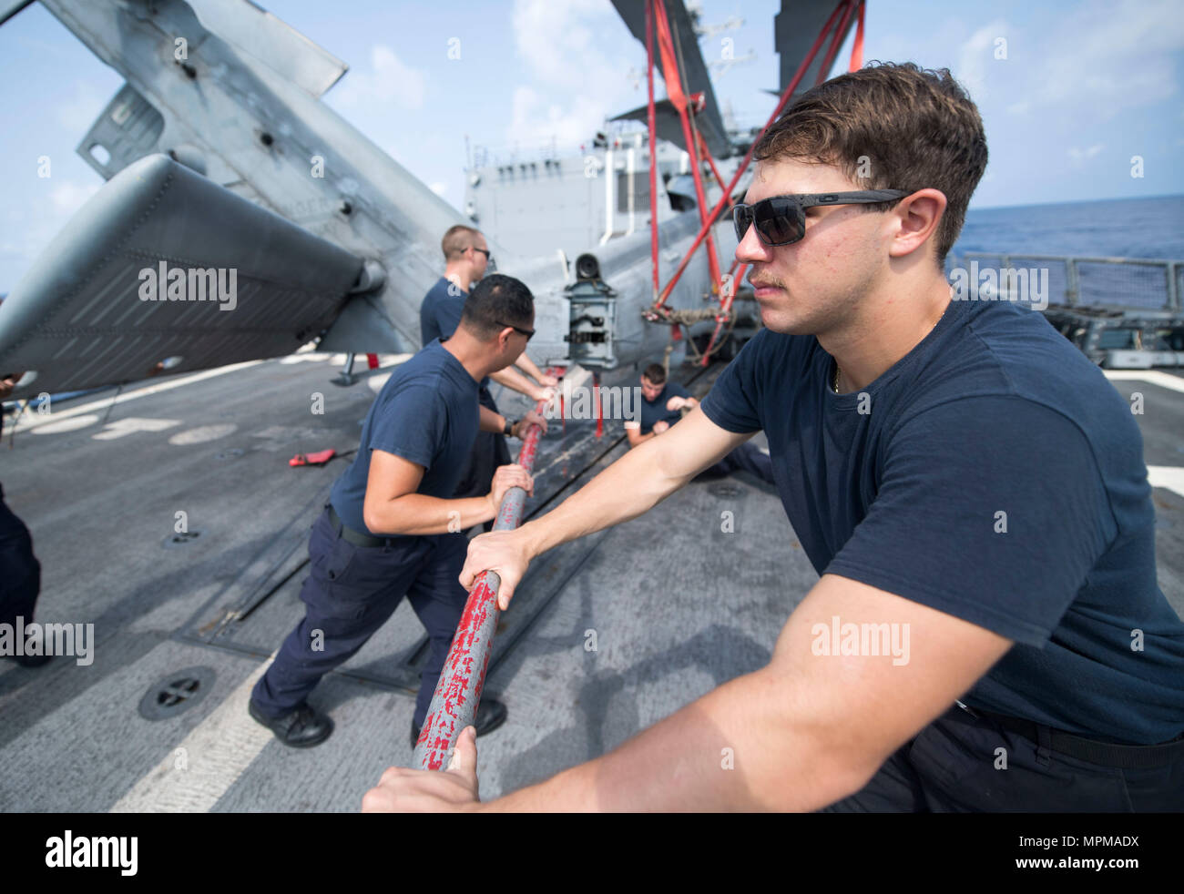 The photograph shows a U.S. Navy Aviation Electrician’s Mate folding ...