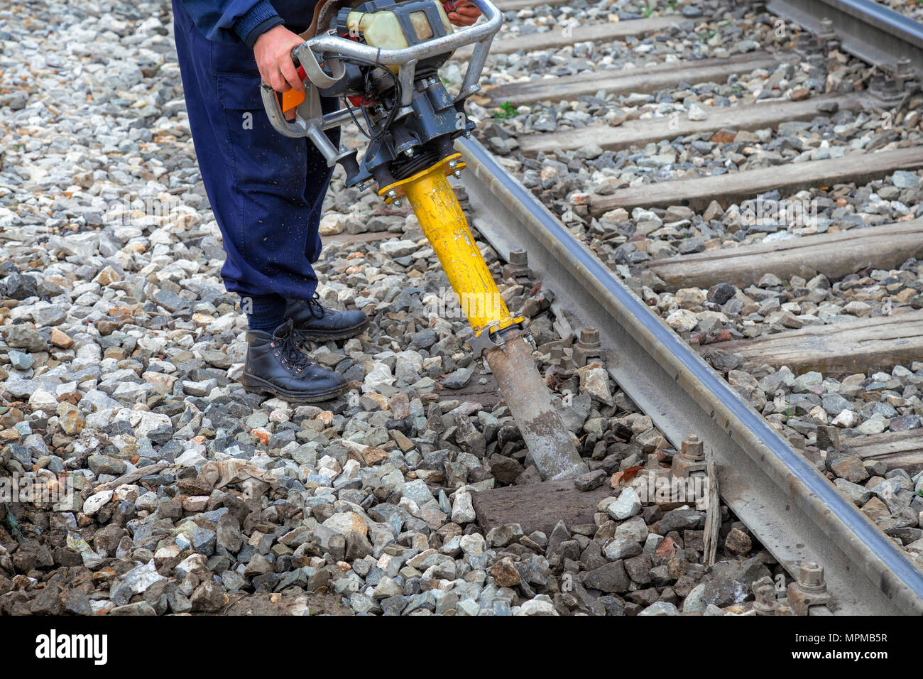 Railroad worker using vertical vibration tamper for a lasting ...