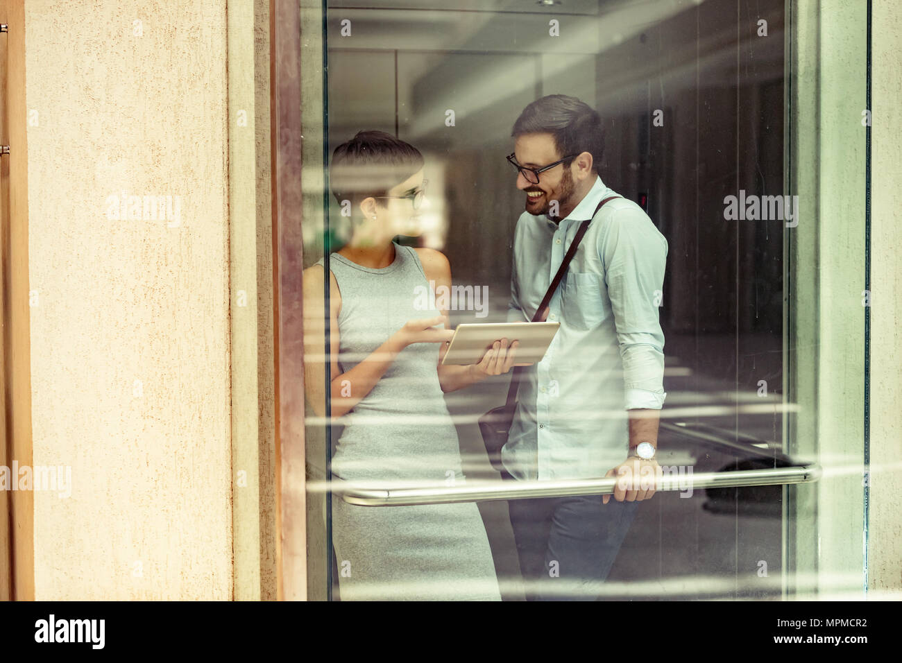 Picture of young businesspeople talking in elevator Stock Photo - Alamy