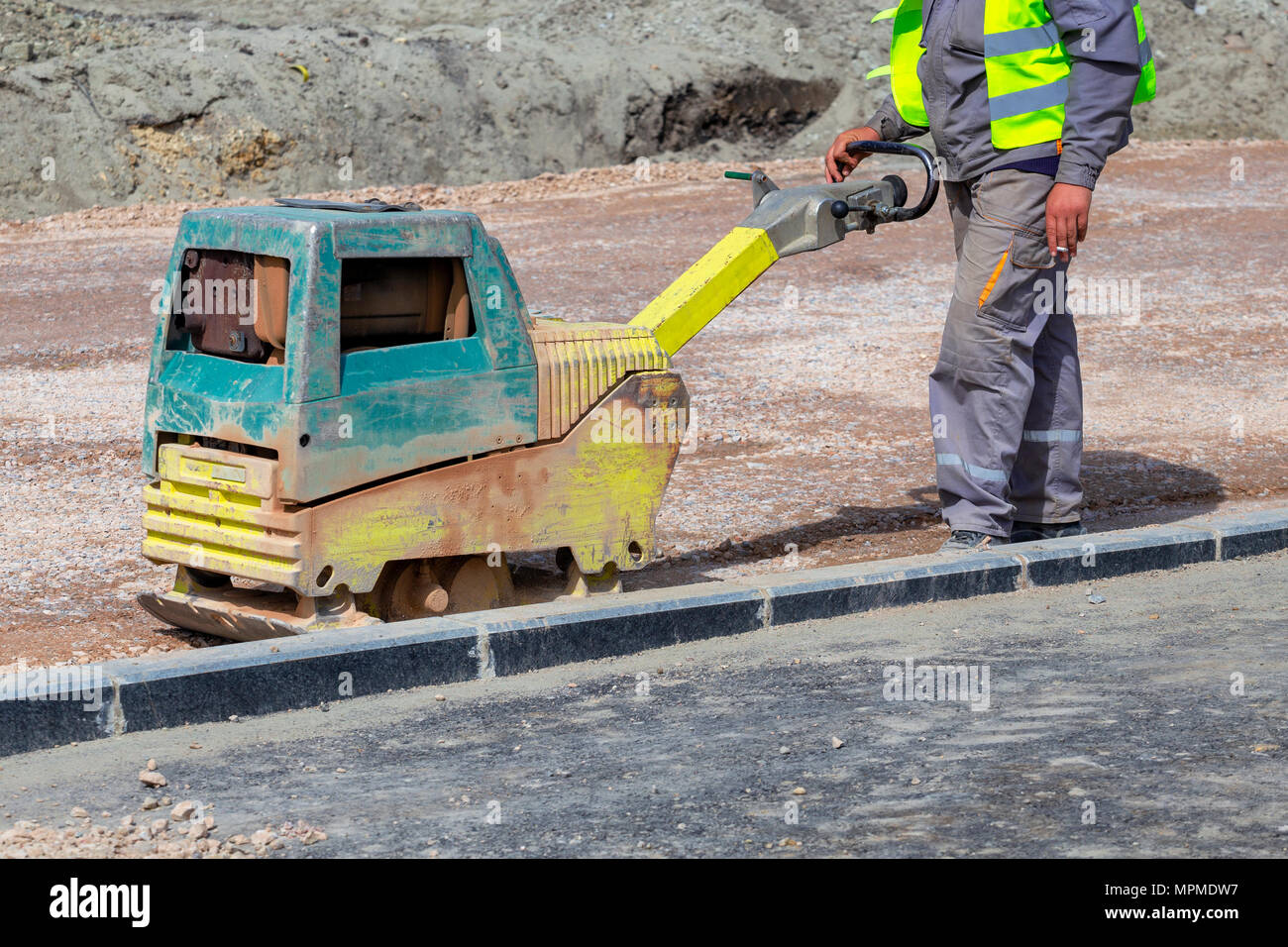 Worker compacting soil using compactor in a city park, sidewalk ...