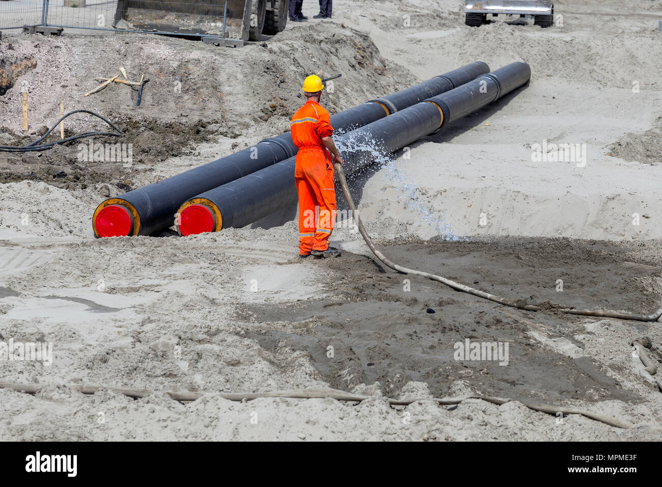 Worker watering at construction site of district heating system ...